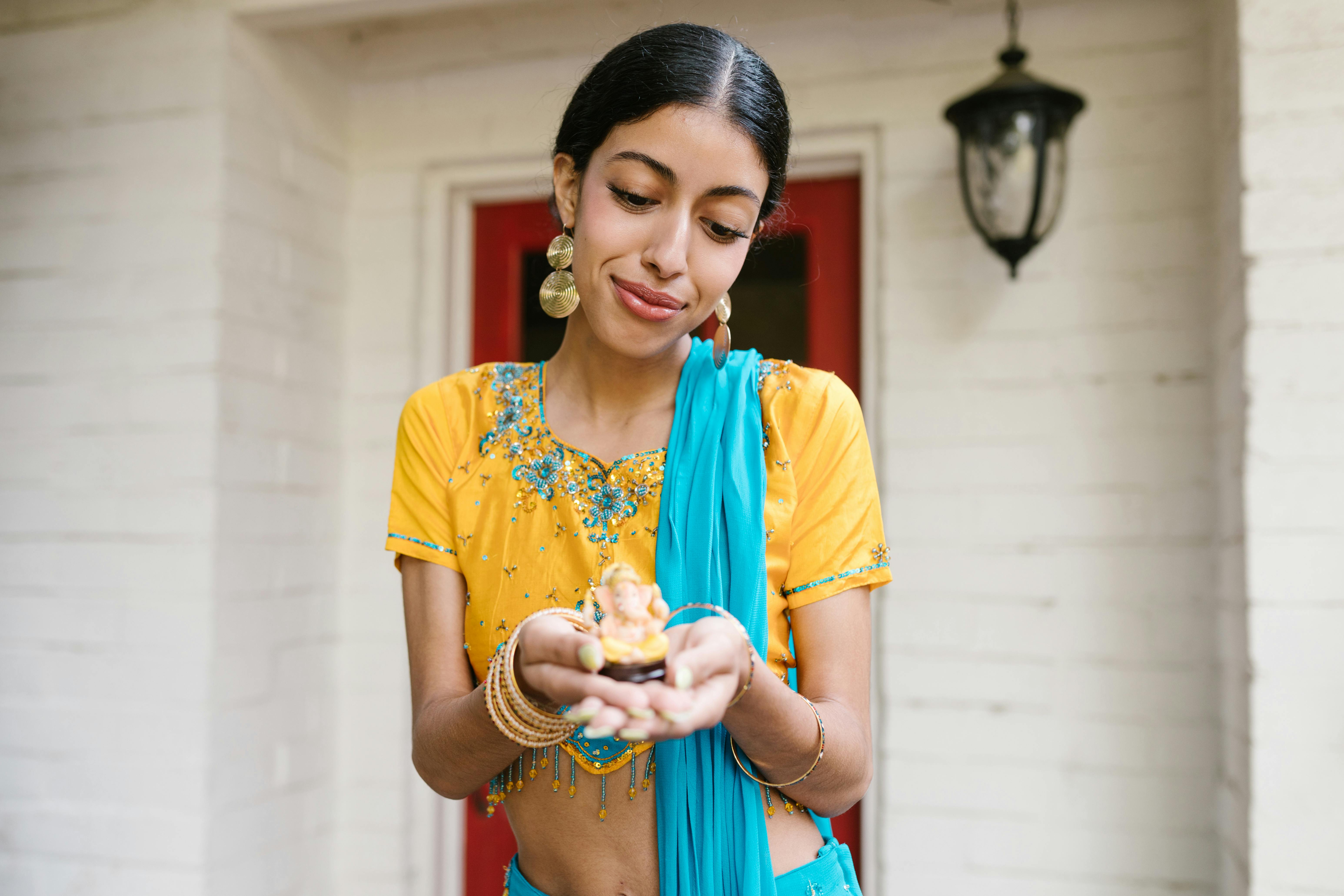 Woman in Yellow Traditional Clothing Holding a Figurine · Free Stock Photo