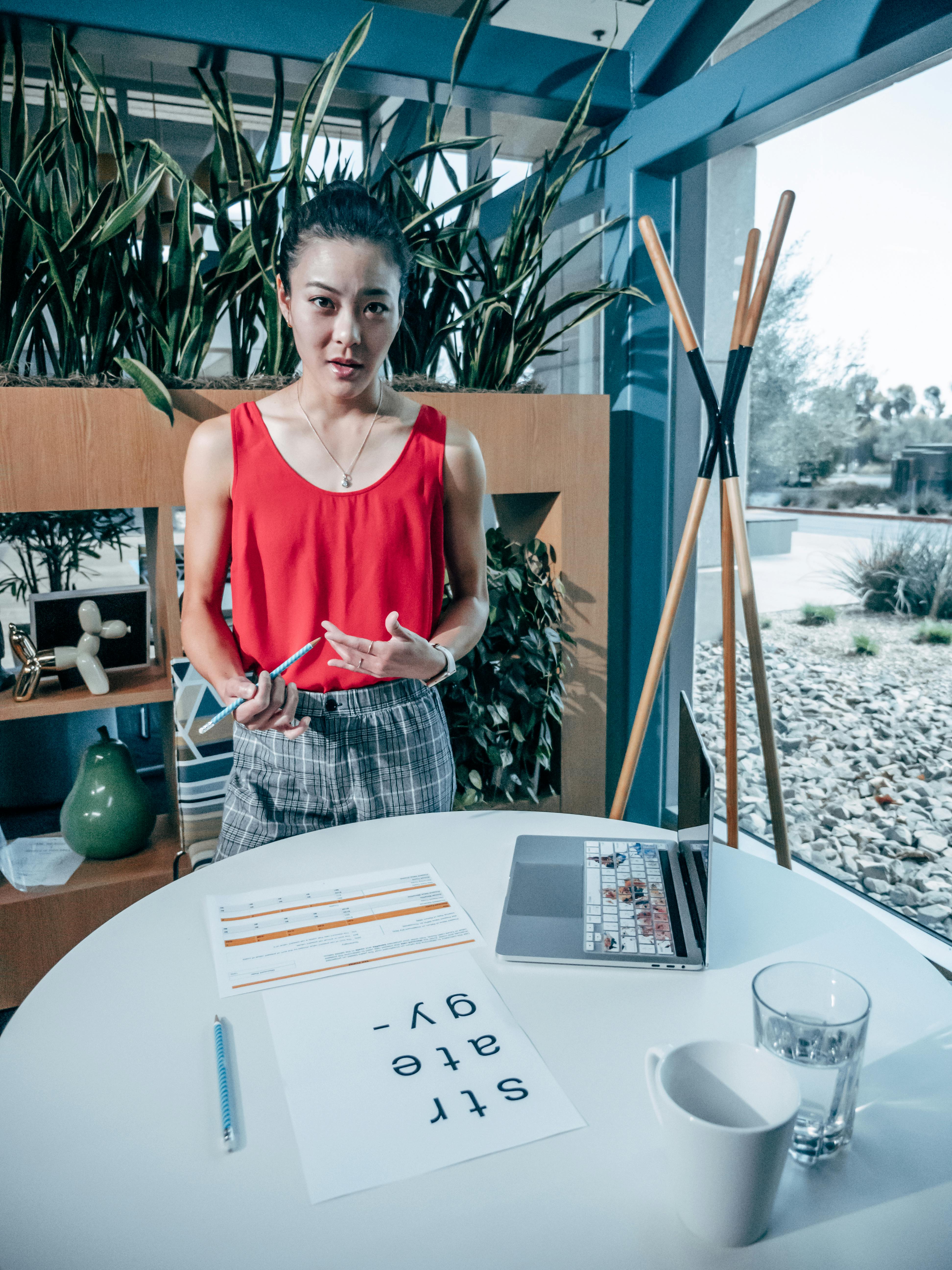 A Woman Standing at the Table with Laptop and Documents · Free Stock Photo
