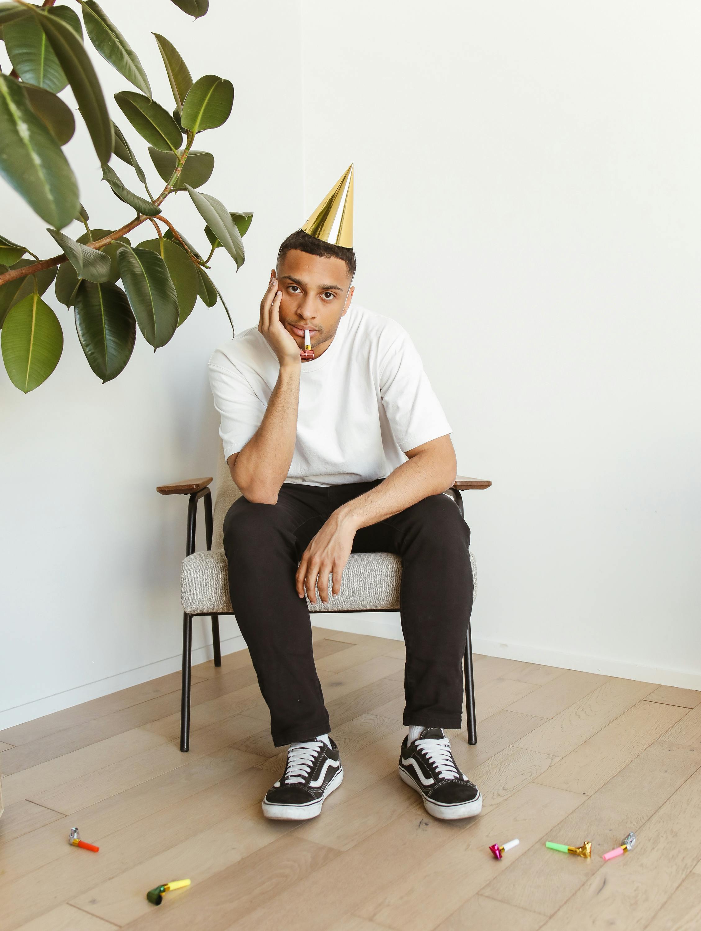 A Man Sitting on the Chair wearing Party Hat · Free Stock Photo