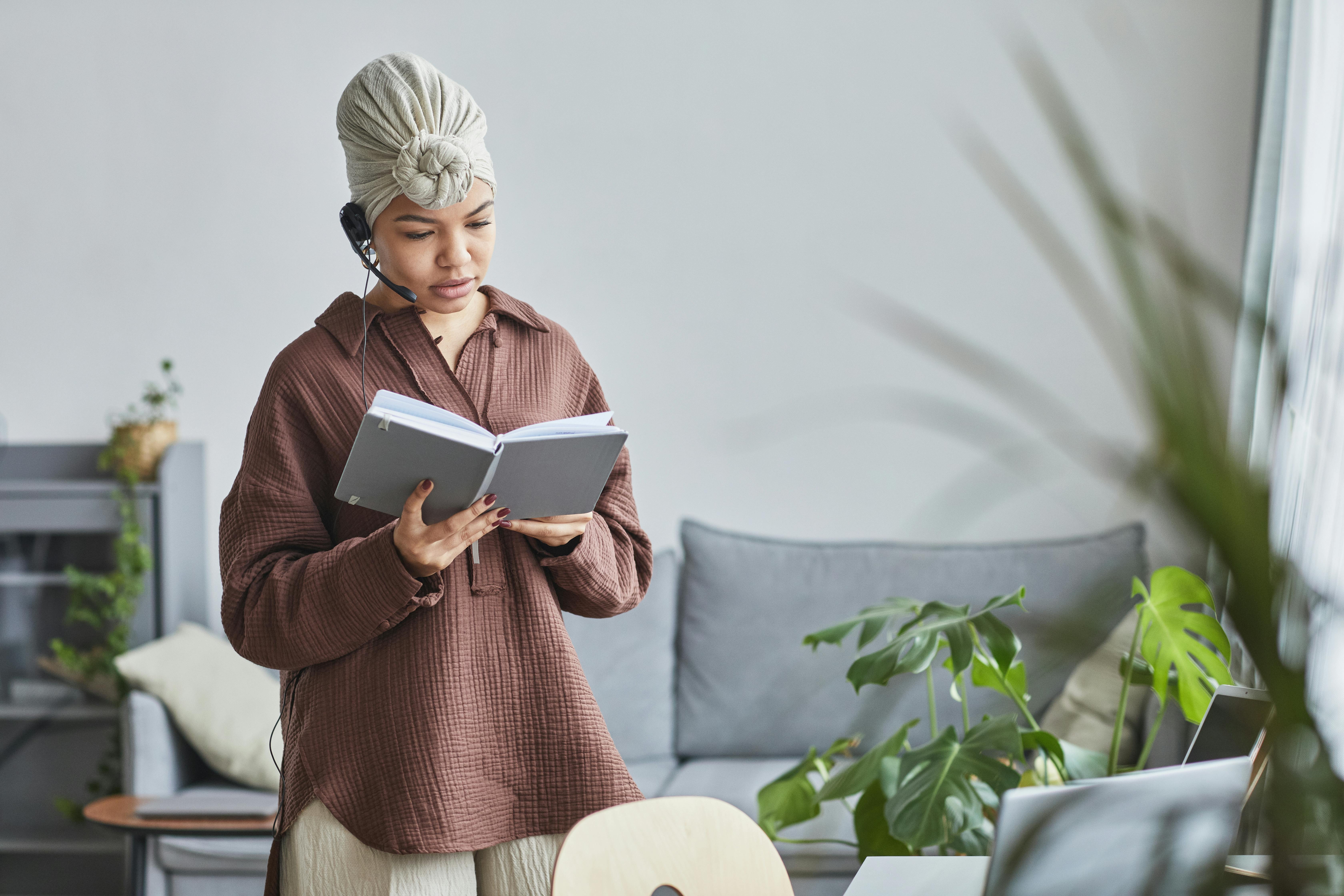 Black woman with headset reading notes from notebook · Free Stock Photo