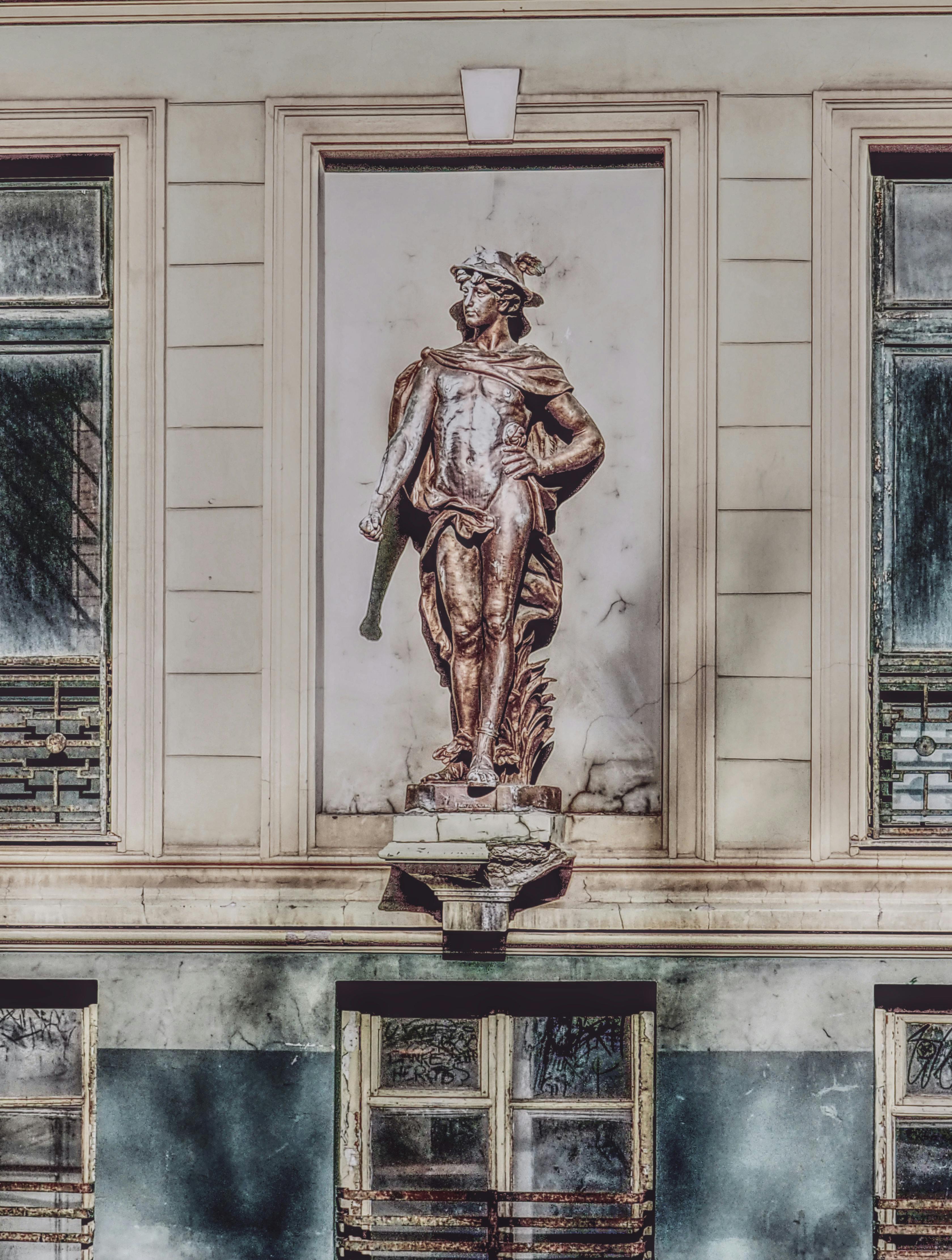 Bronze Sculpture of Man on Building Wall · Free Stock Photo