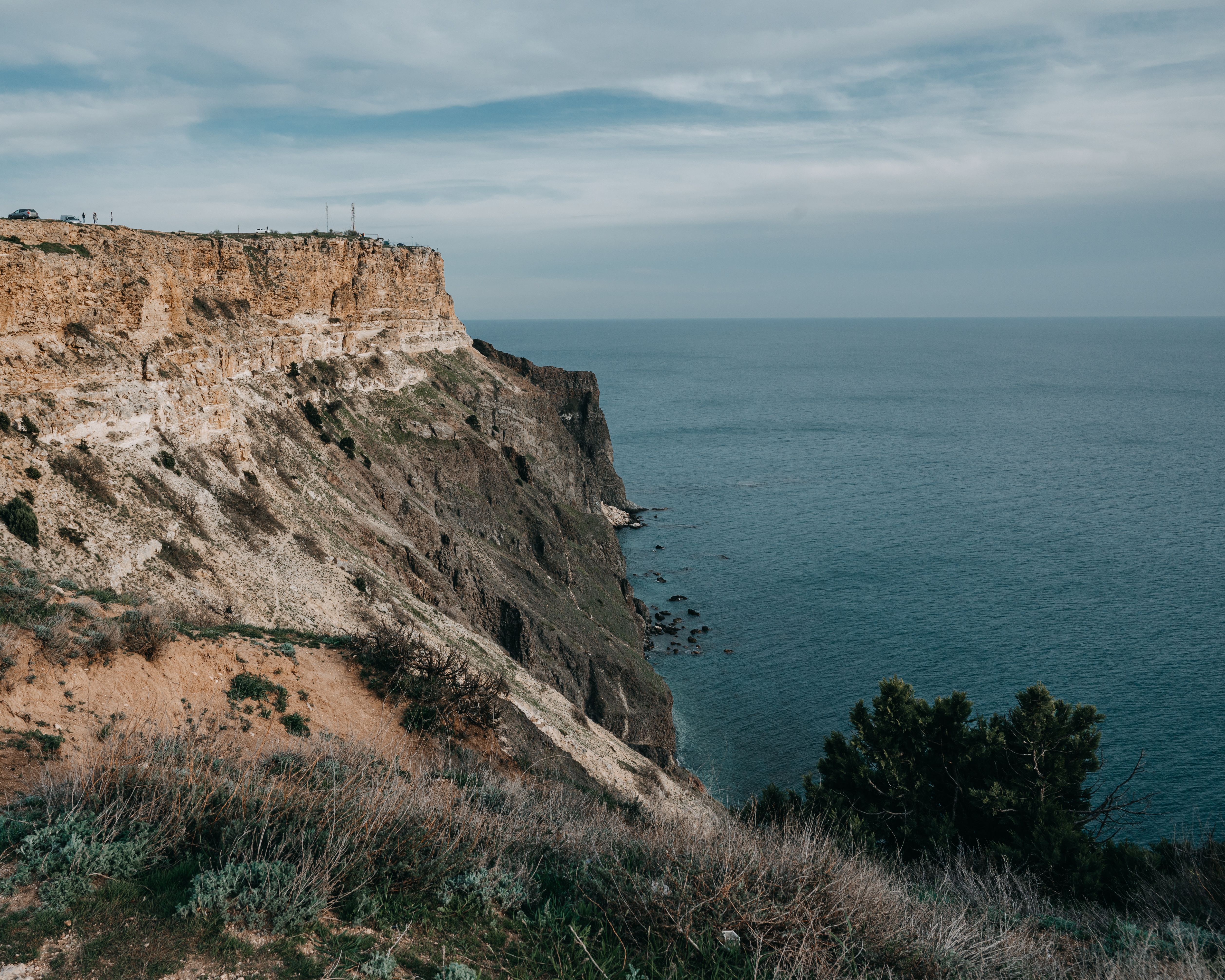 Rough cliff near endless water of ocean under cloudy sky · Free Stock Photo