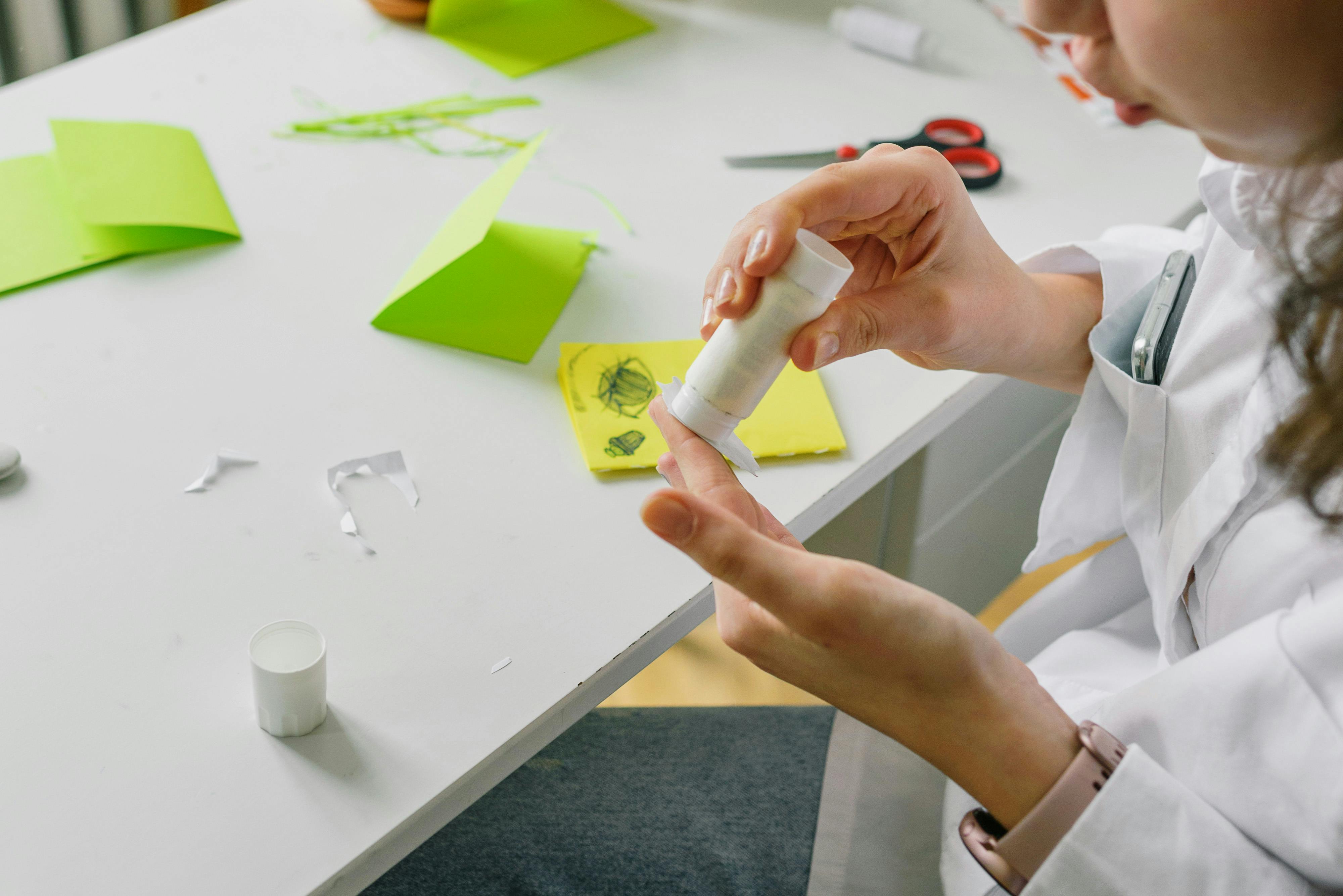 Person Sticking Paper on Cardboard Using a Glue Gun · Free Stock Photo
