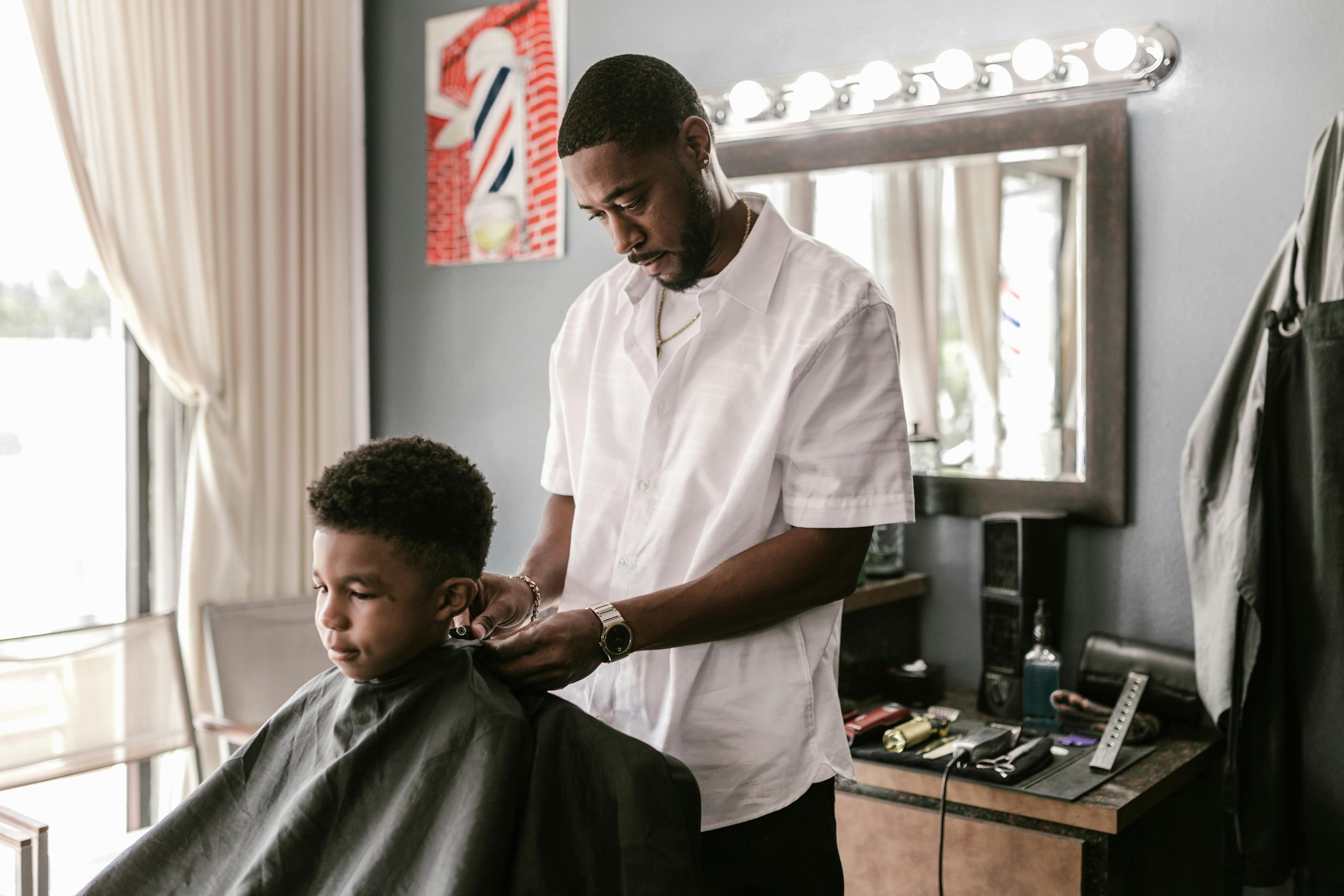 Unrecognizable barber cutting beard to ethnic client in poor barbershop ...