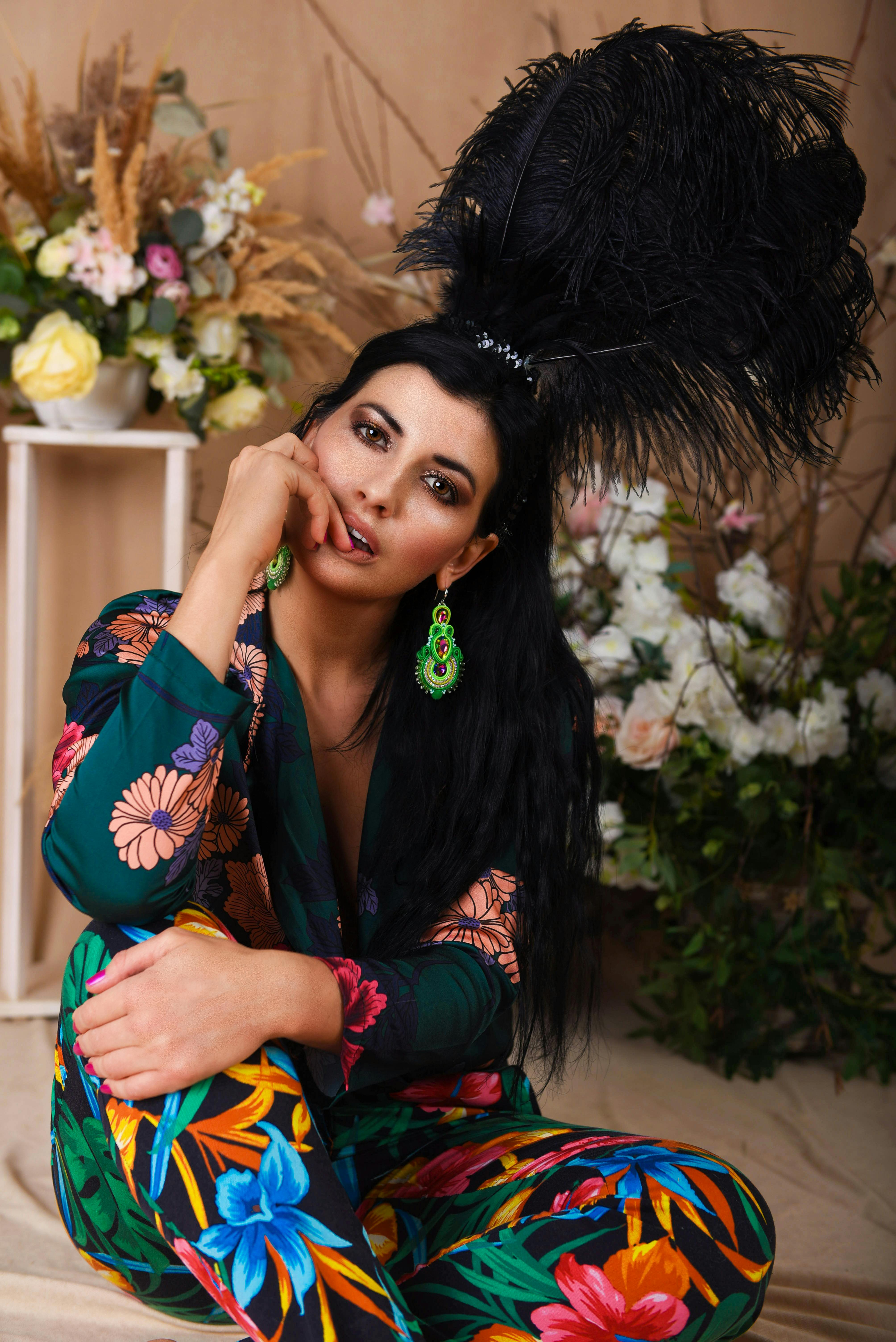 Woman in stylish outfit embracing knee and looking at camera against ...