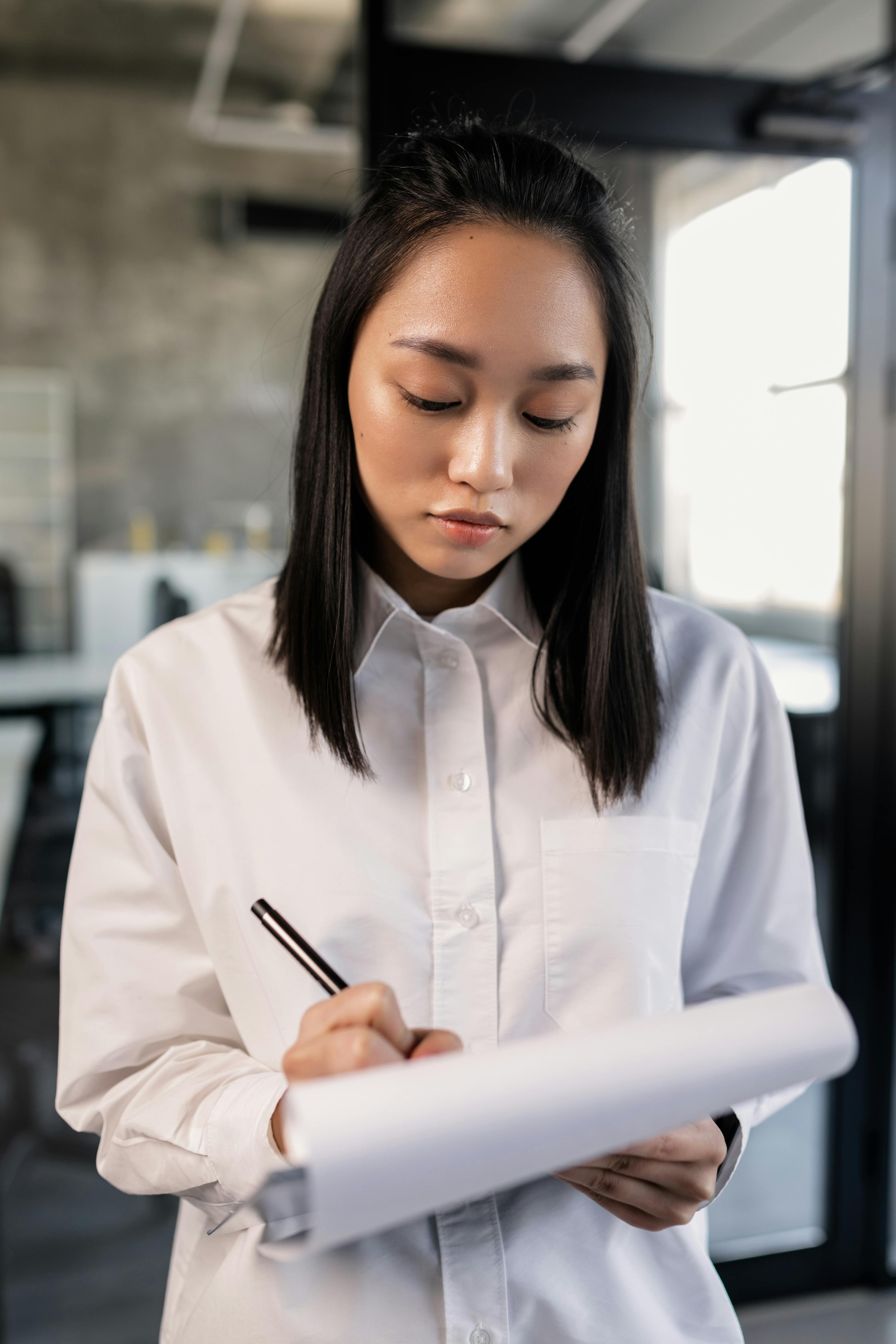 A Woman in White Long Sleeves Writing on Paper · Free Stock Photo
