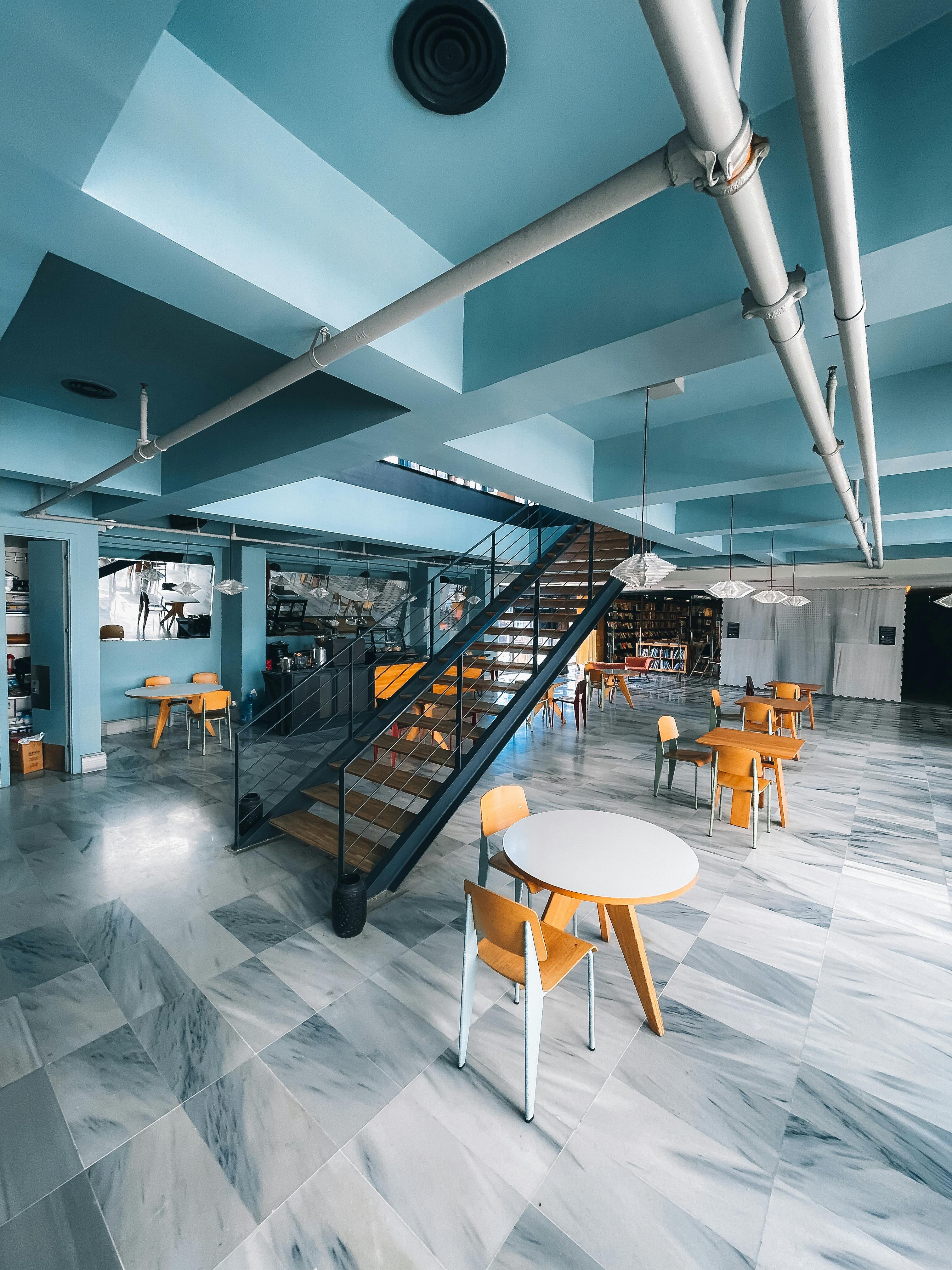 Tables with chairs in modern cafeteria with stairs · Free Stock Photo
