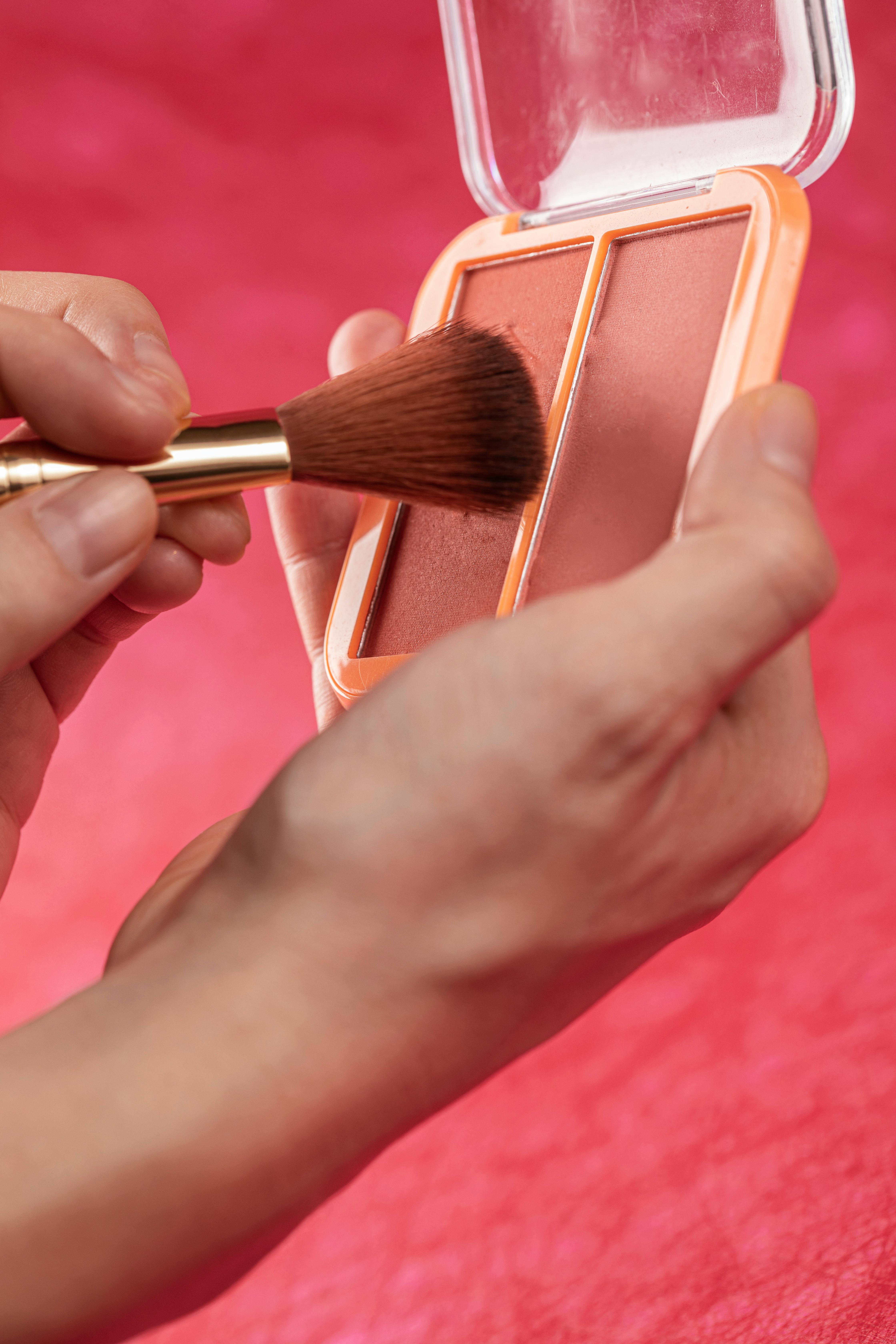 A Person Holding a Makeup Brush and Blush On · Free Stock Photo