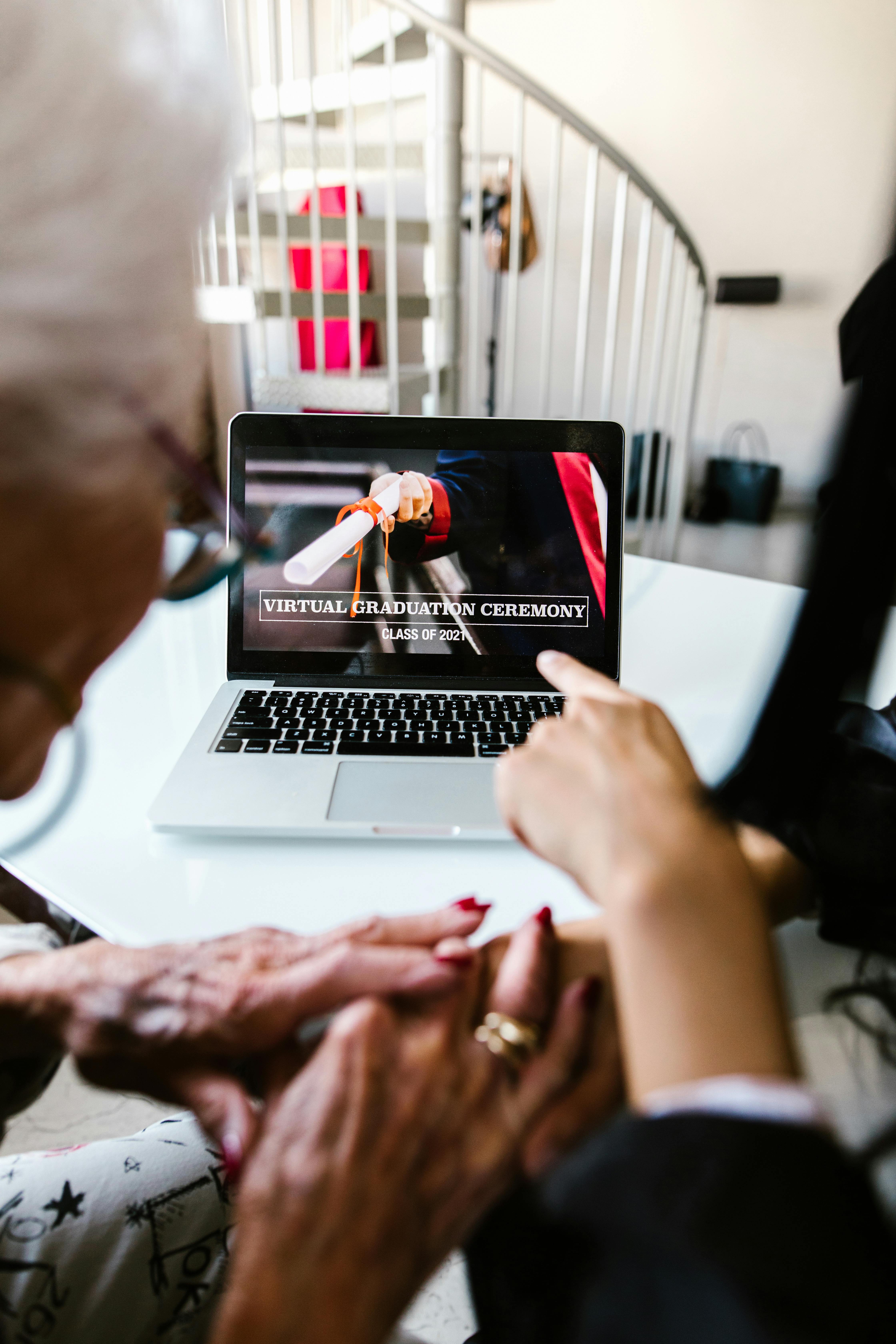 Women Watching Graduation Ceremony Video on Laptop · Free Stock Photo