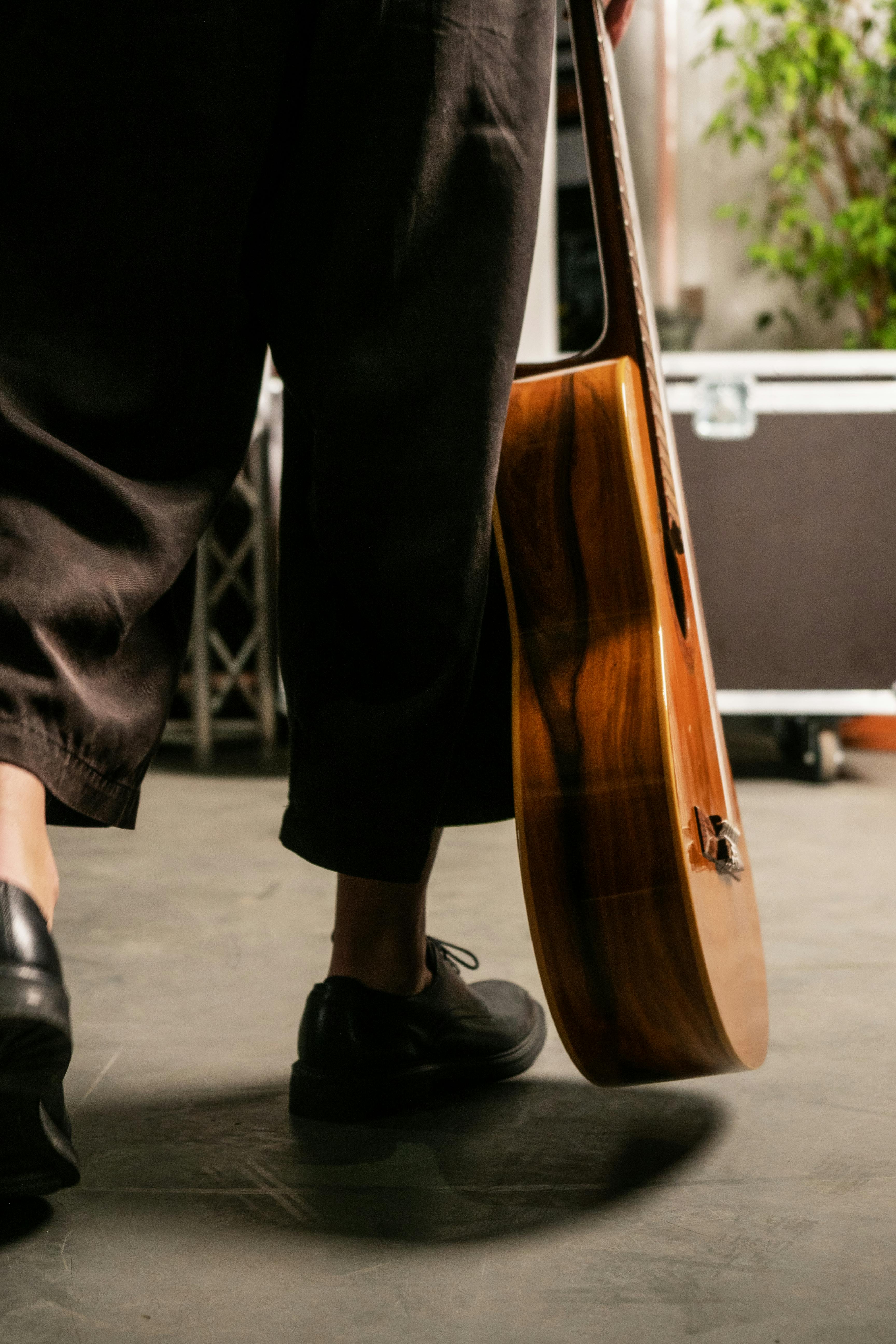 Person Walking Carrying a Brown Acoustic Guitar · Free Stock Photo