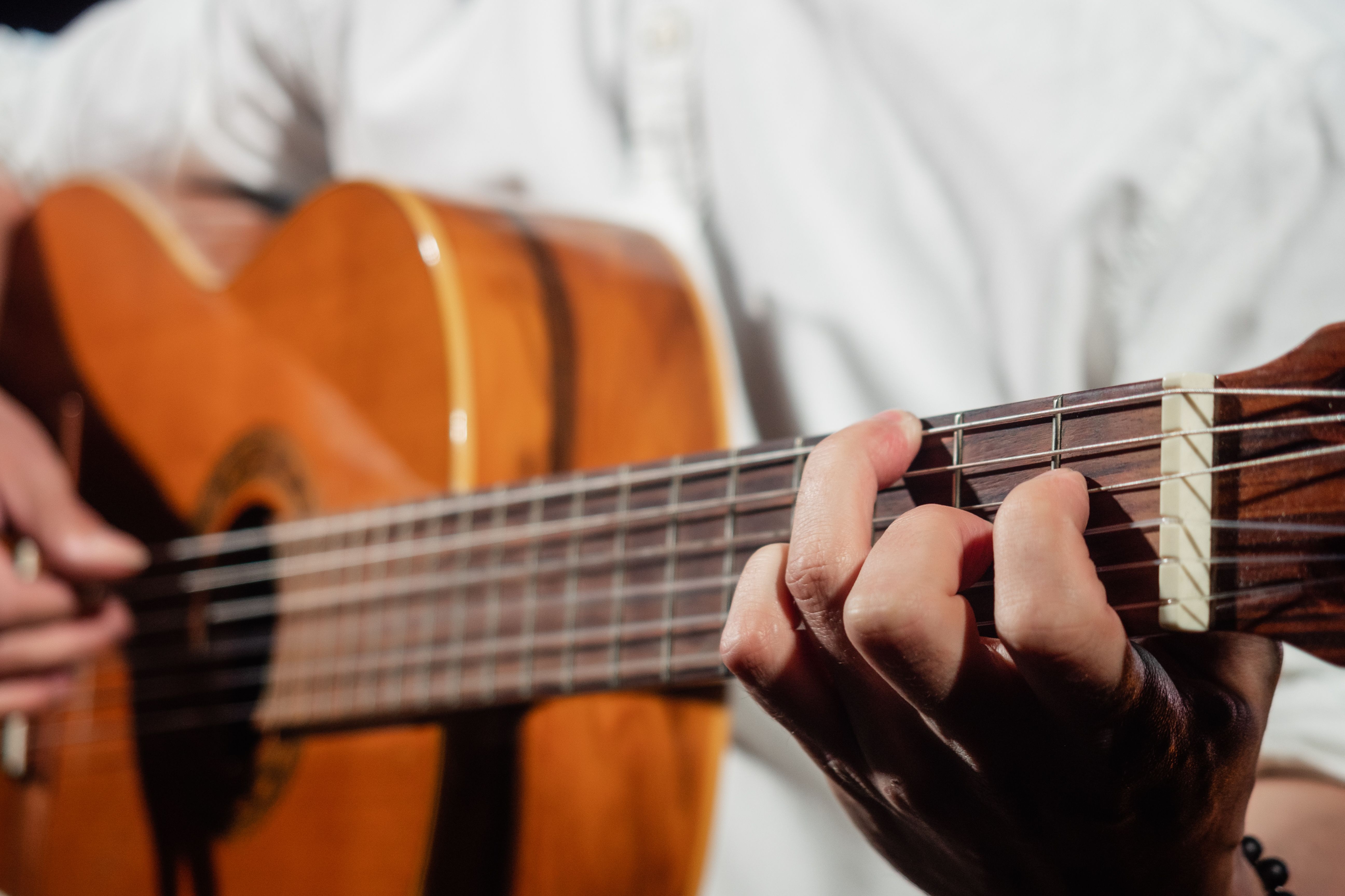 A Back View of a Person Sitting while Playing Guitar · Free Stock Photo