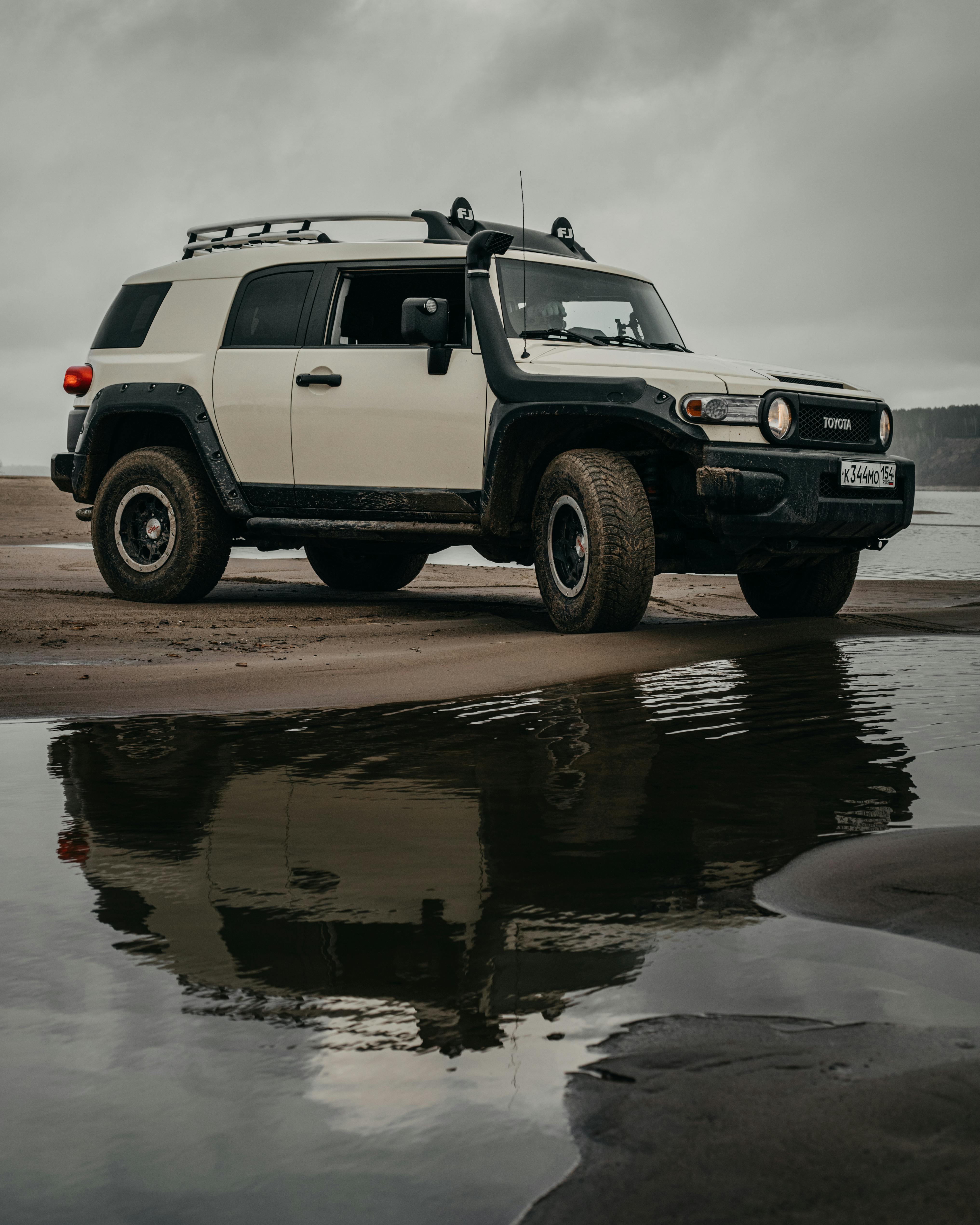 Car parked on seashore near mountains in foggy weather · Free Stock Photo