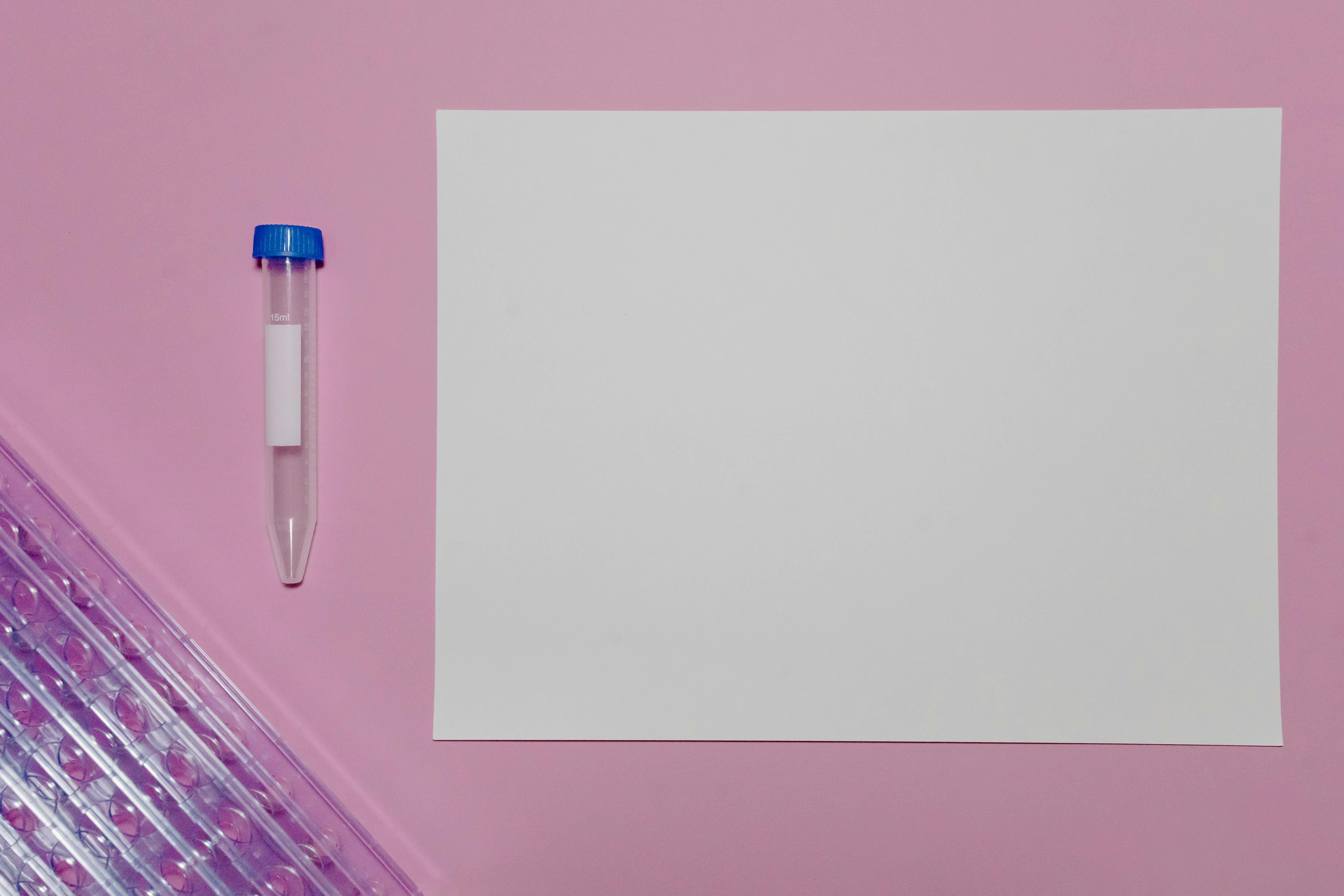 Plastic Test Tube Beside the White Paper · Free Stock Photo
