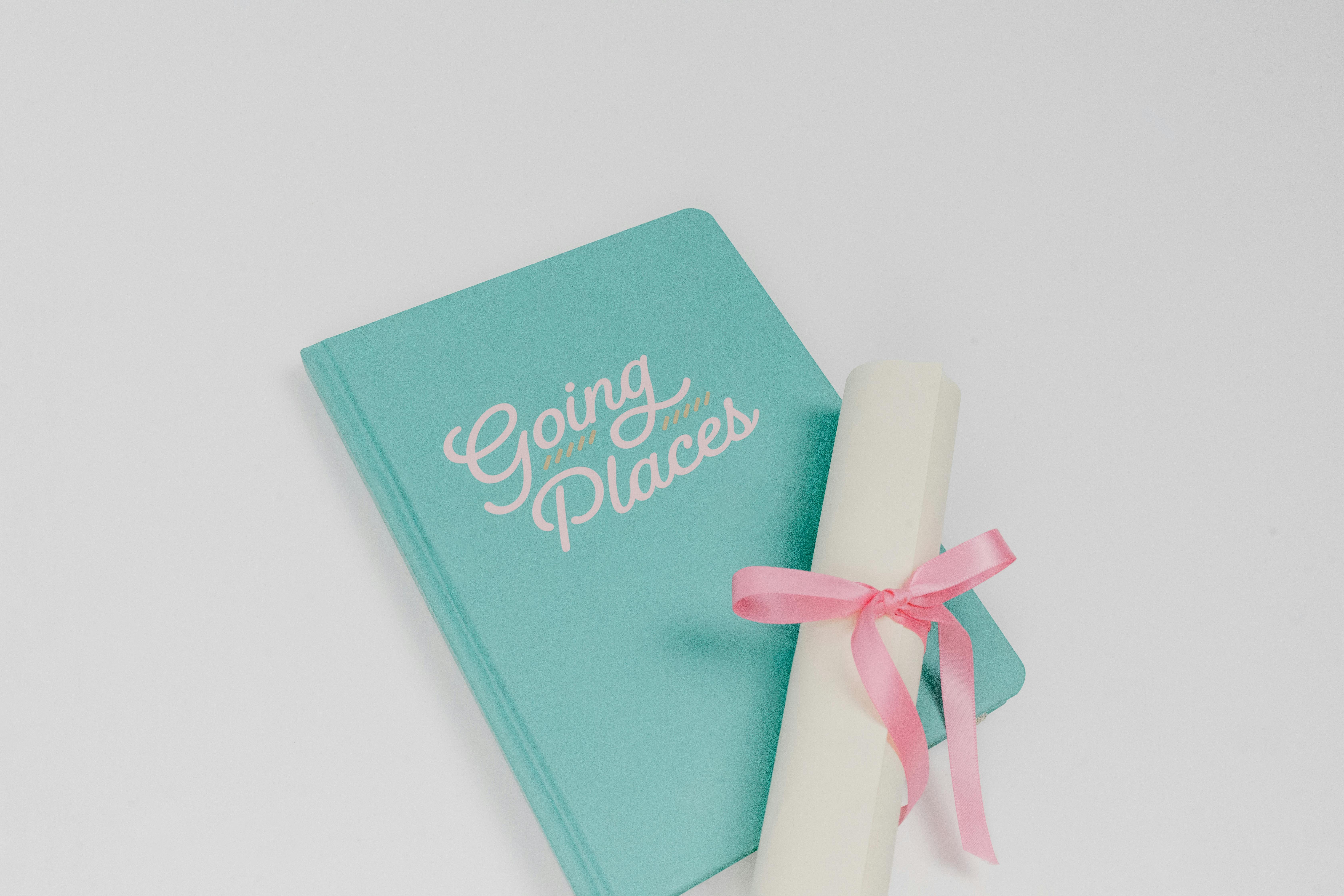 Green Notebook and White Rolled Paper with Pink Ribbon · Free Stock Photo