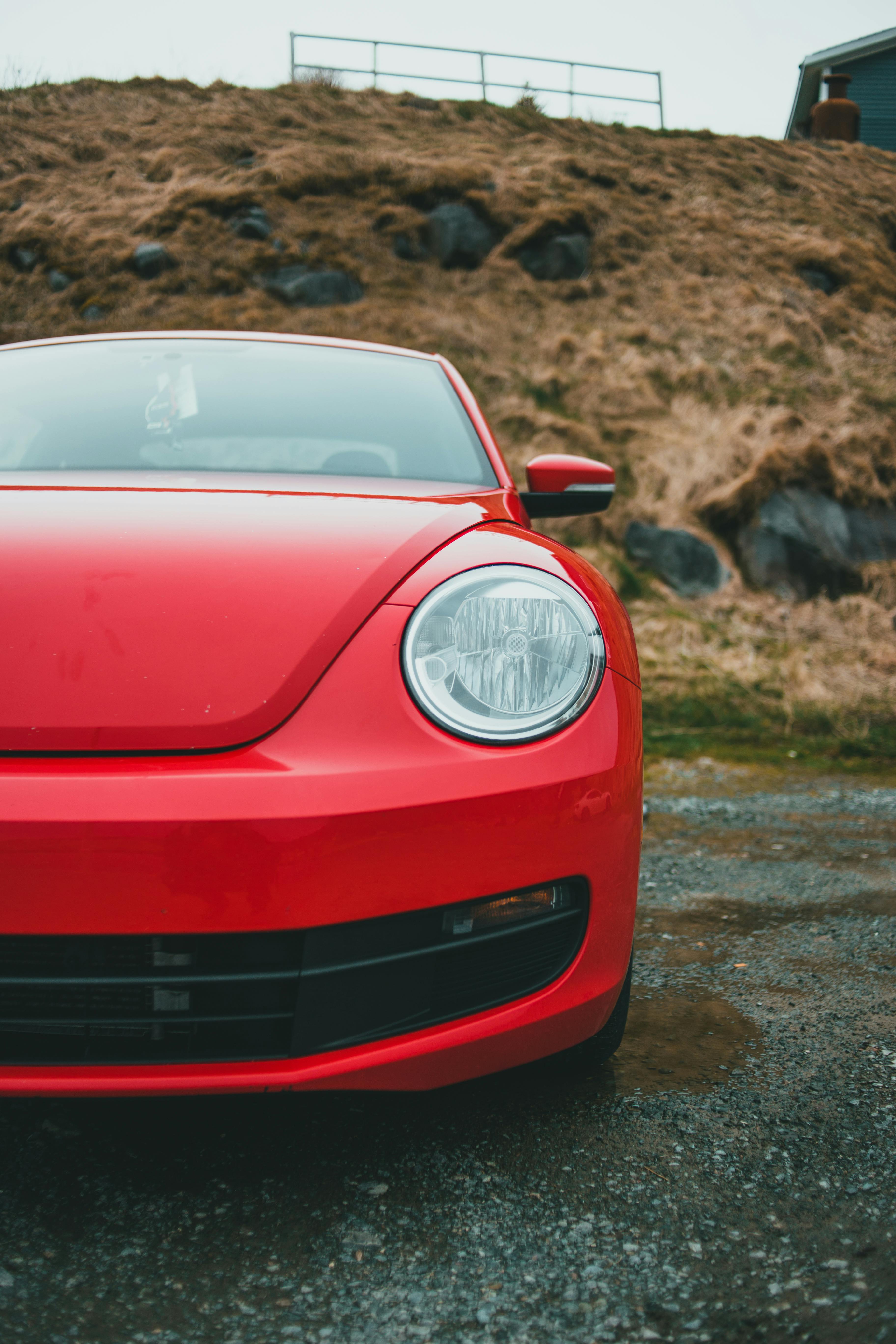 Red car parked near grassy slope · Free Stock Photo