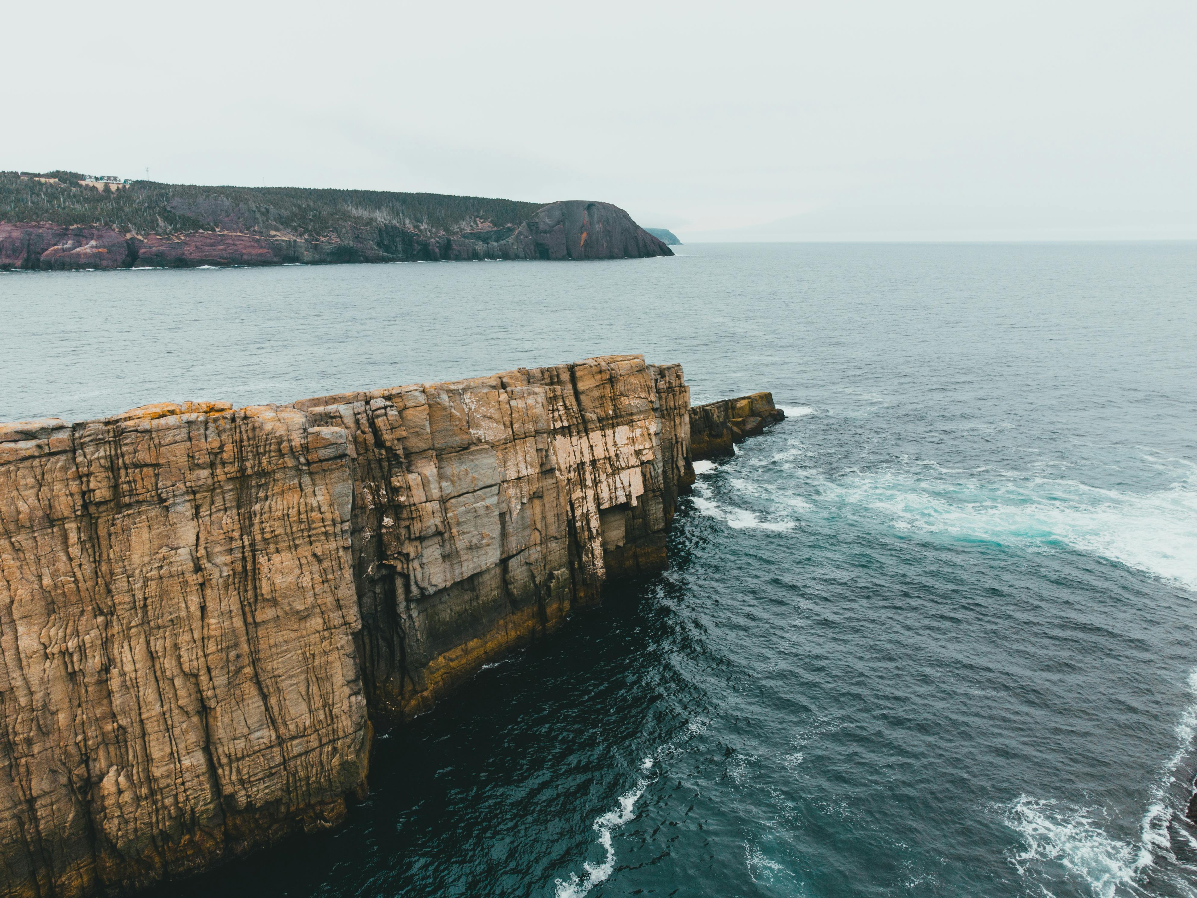 Rock Cliff Near Ocean With Kayakers and Speed Boat Passing · Free Stock ...