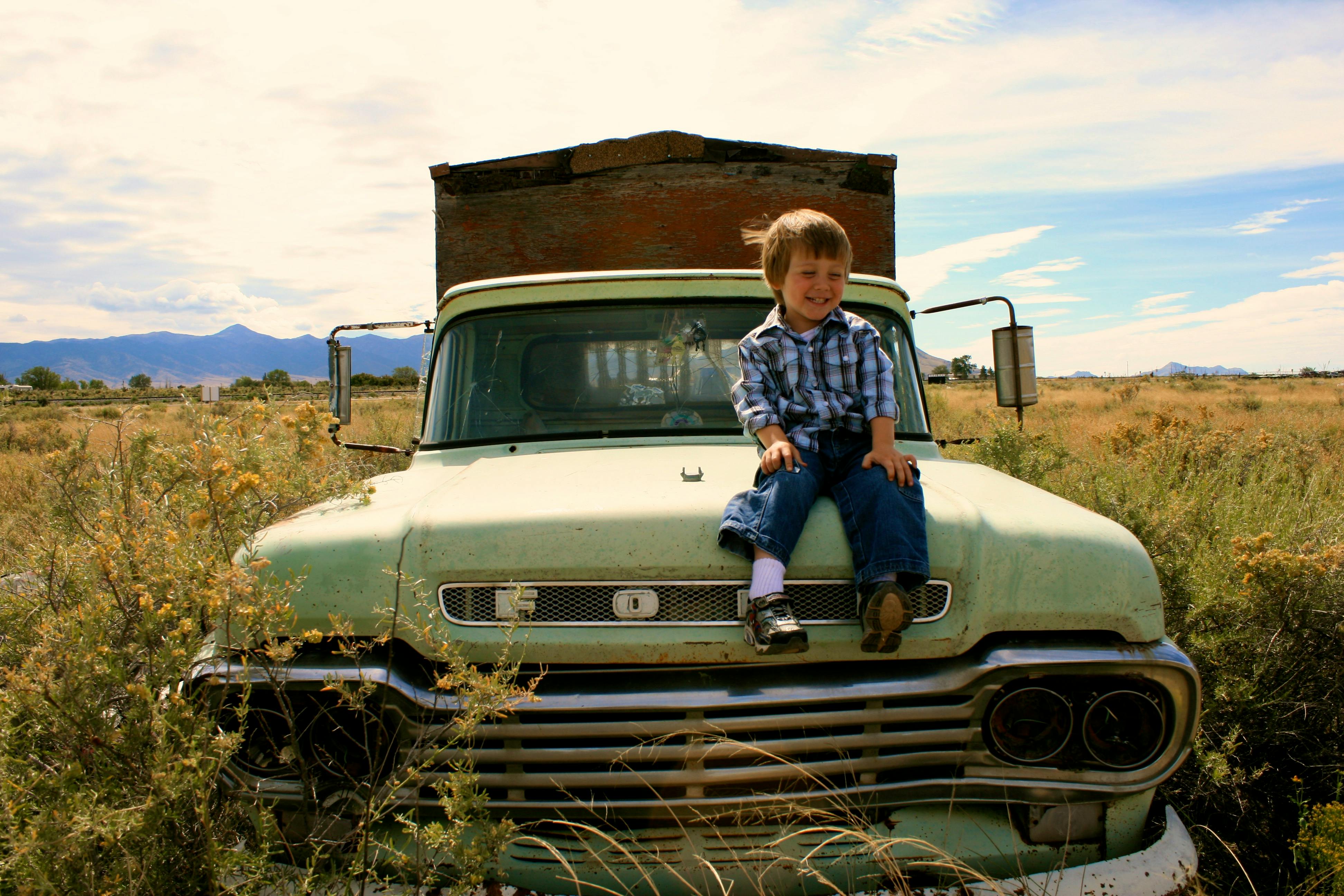A Young Boy Sitting on the Front of a Pickup Truck · Free Stock Photo