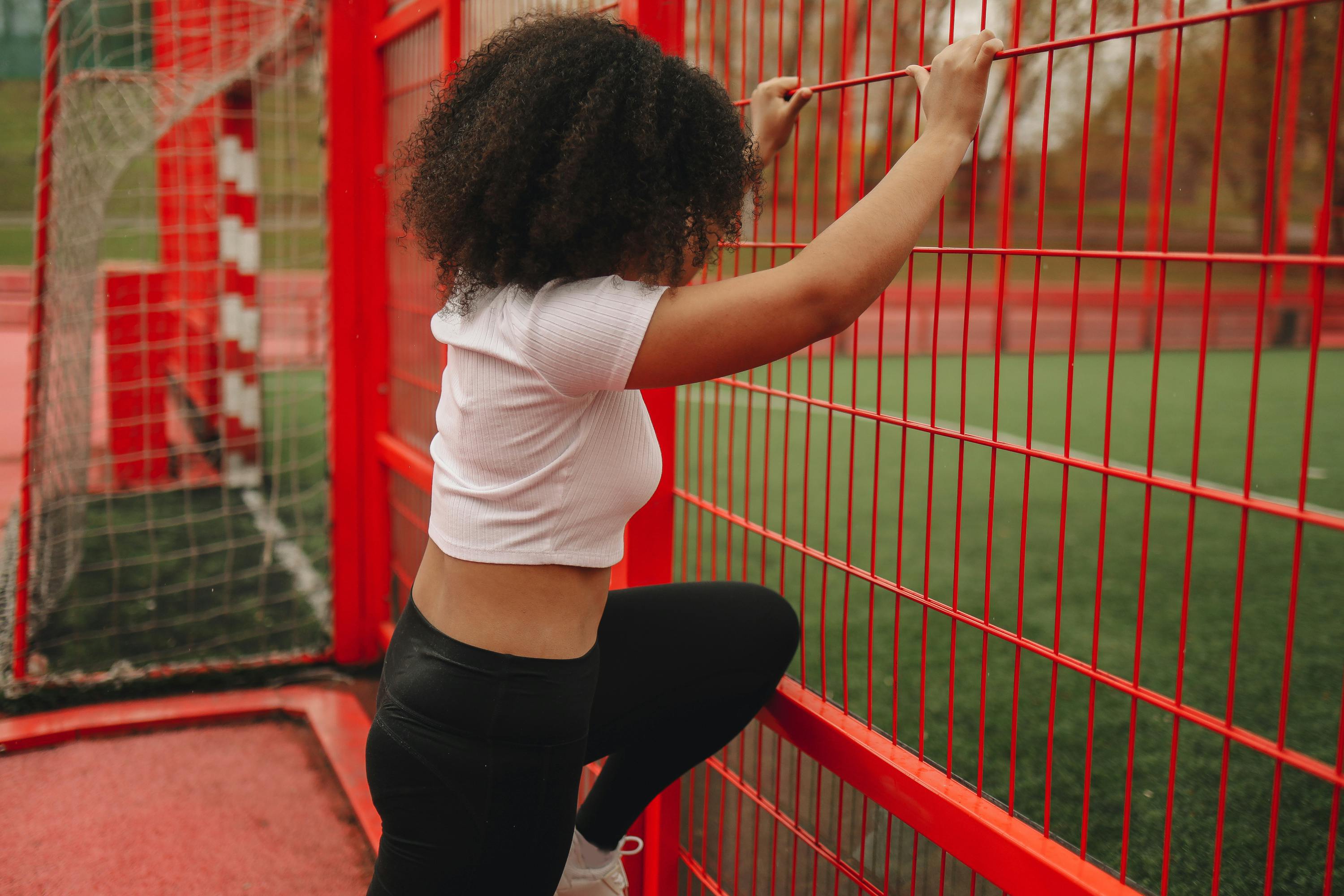 Woman Leaning on Fence and Stretching · Free Stock Photo