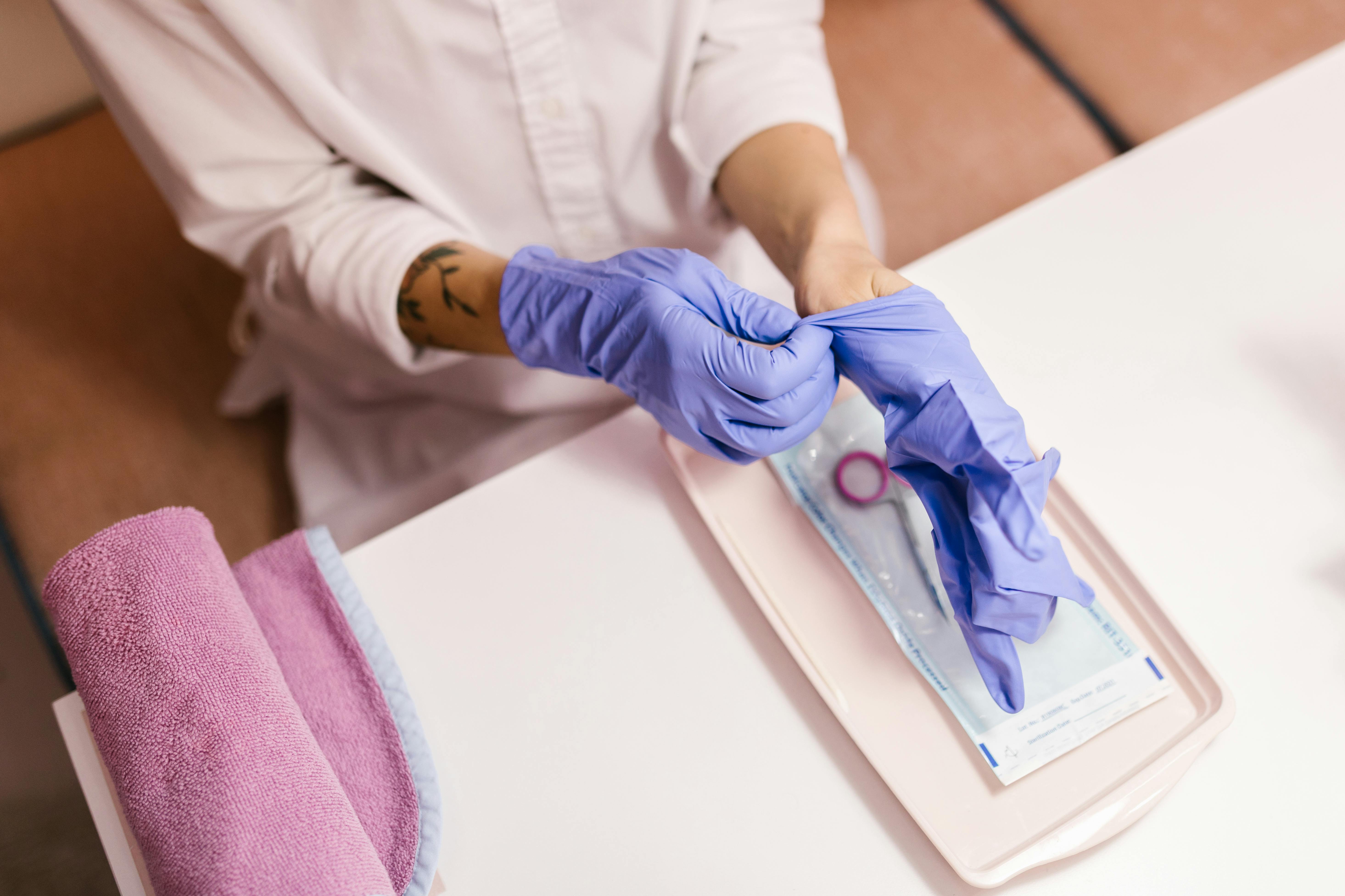 Person in White Long Sleeves Putting Blue Latex Gloves · Free Stock Photo