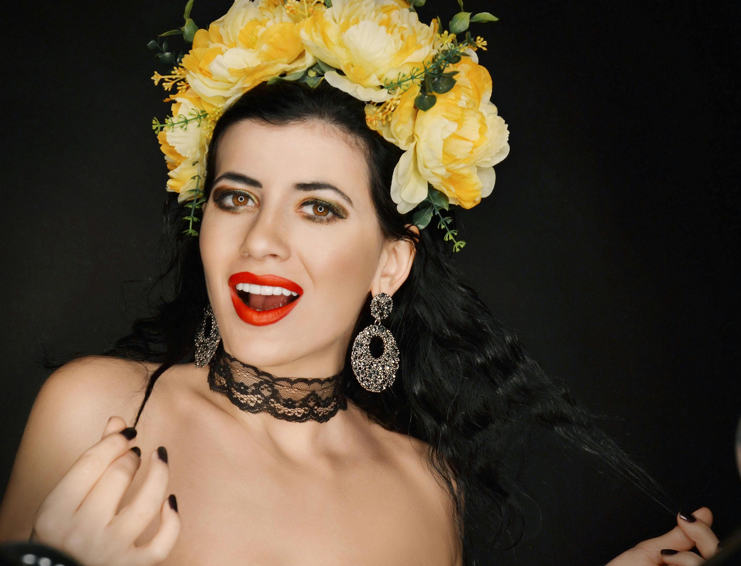 Extravagant woman with bright makeup and flower wreath looking at ...