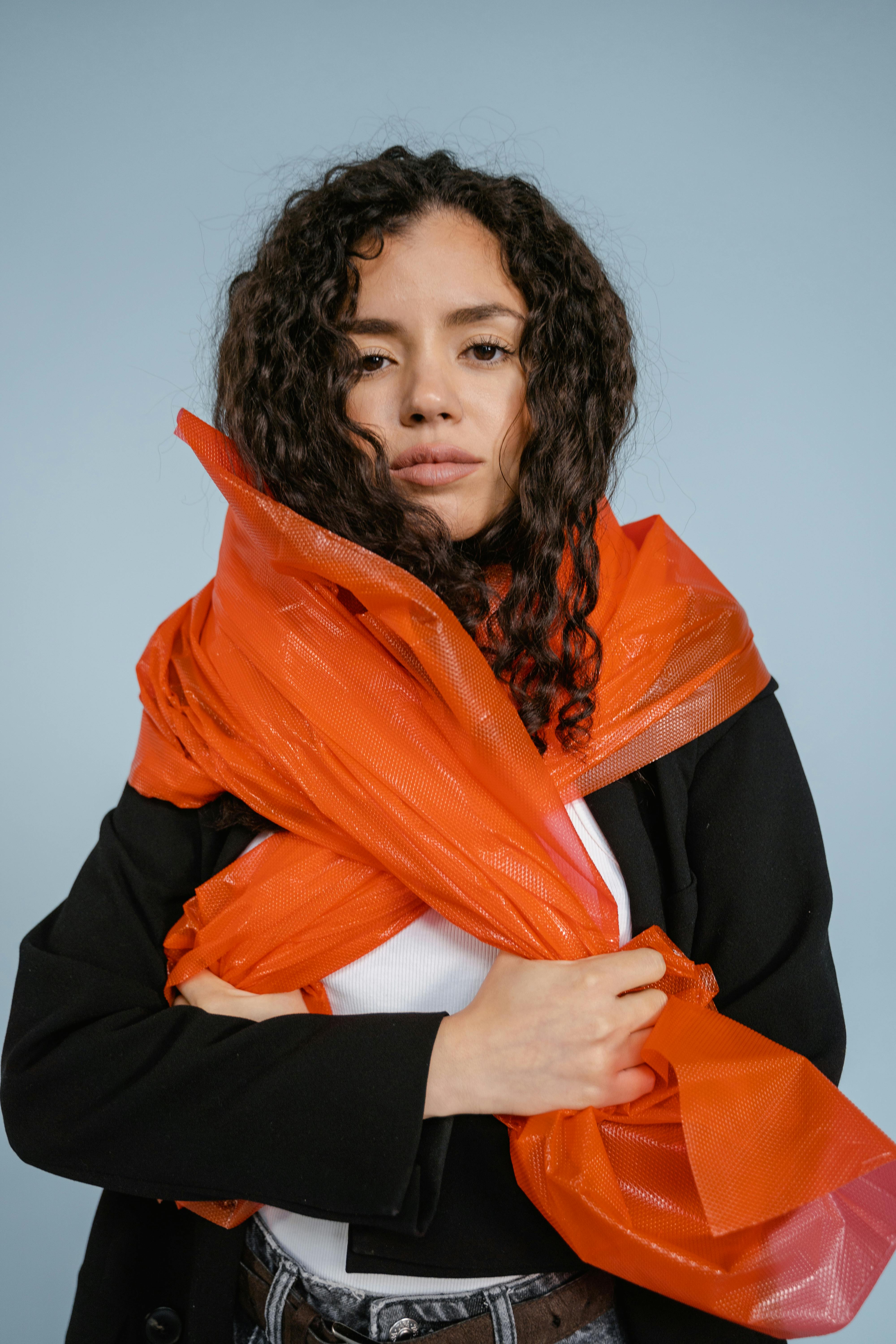 A Young Woman Posing in Black Coat Holding a Red Fabric Wrap Around Her ...