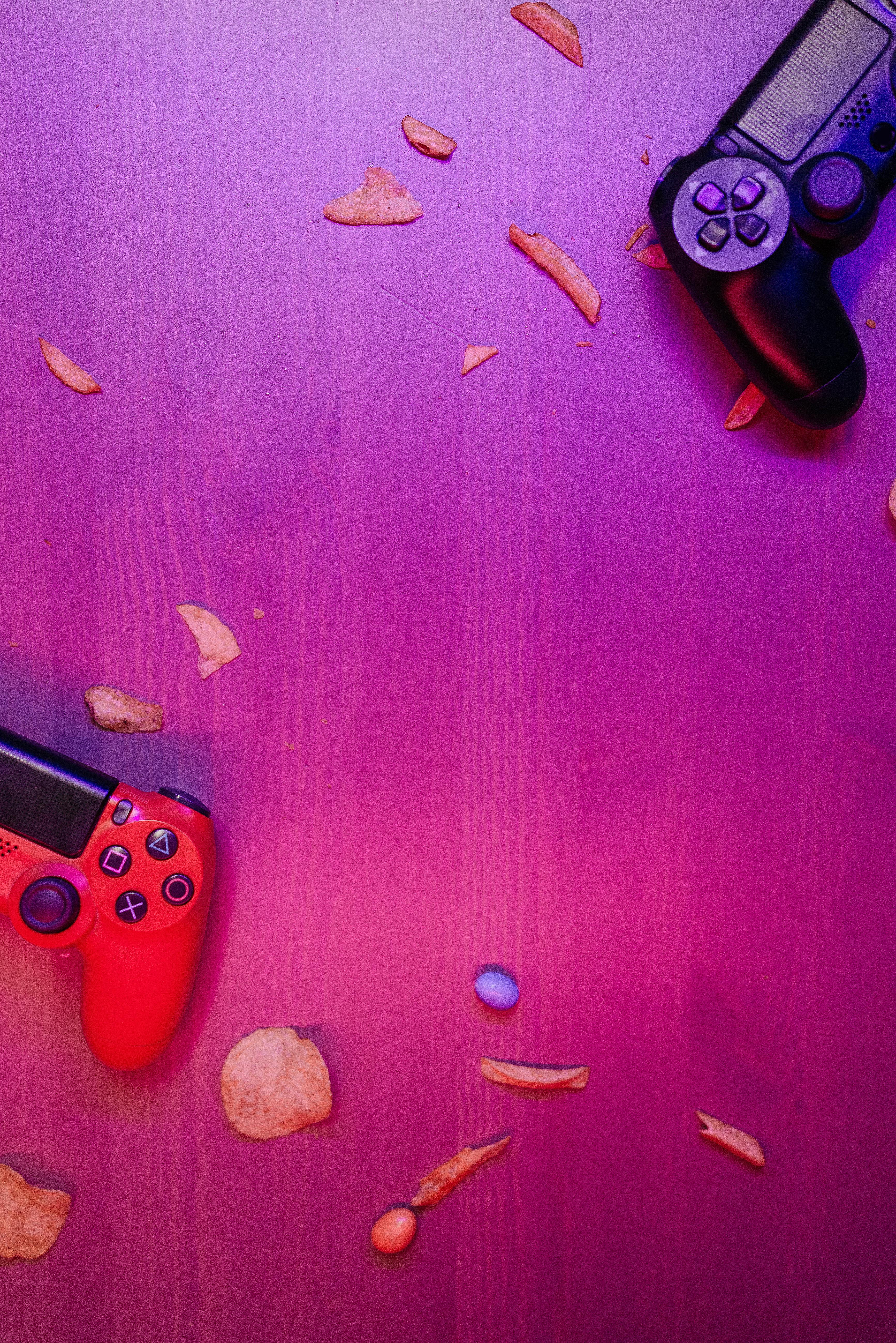 A Red and Black Game Controllers on a Messy Wooden Table · Free Stock Photo