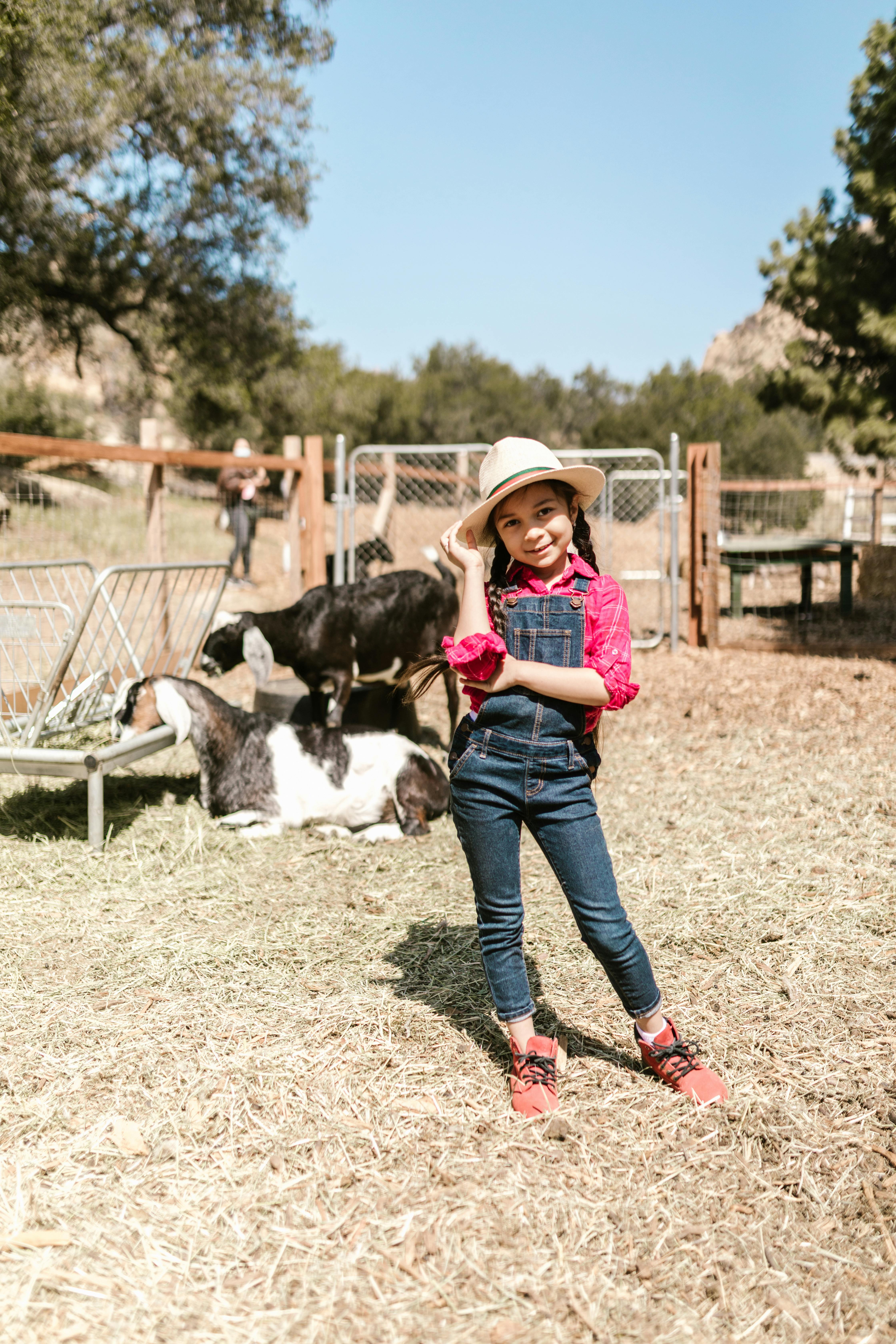 Smile Girl in Overalls Standing on Farm · Free Stock Photo