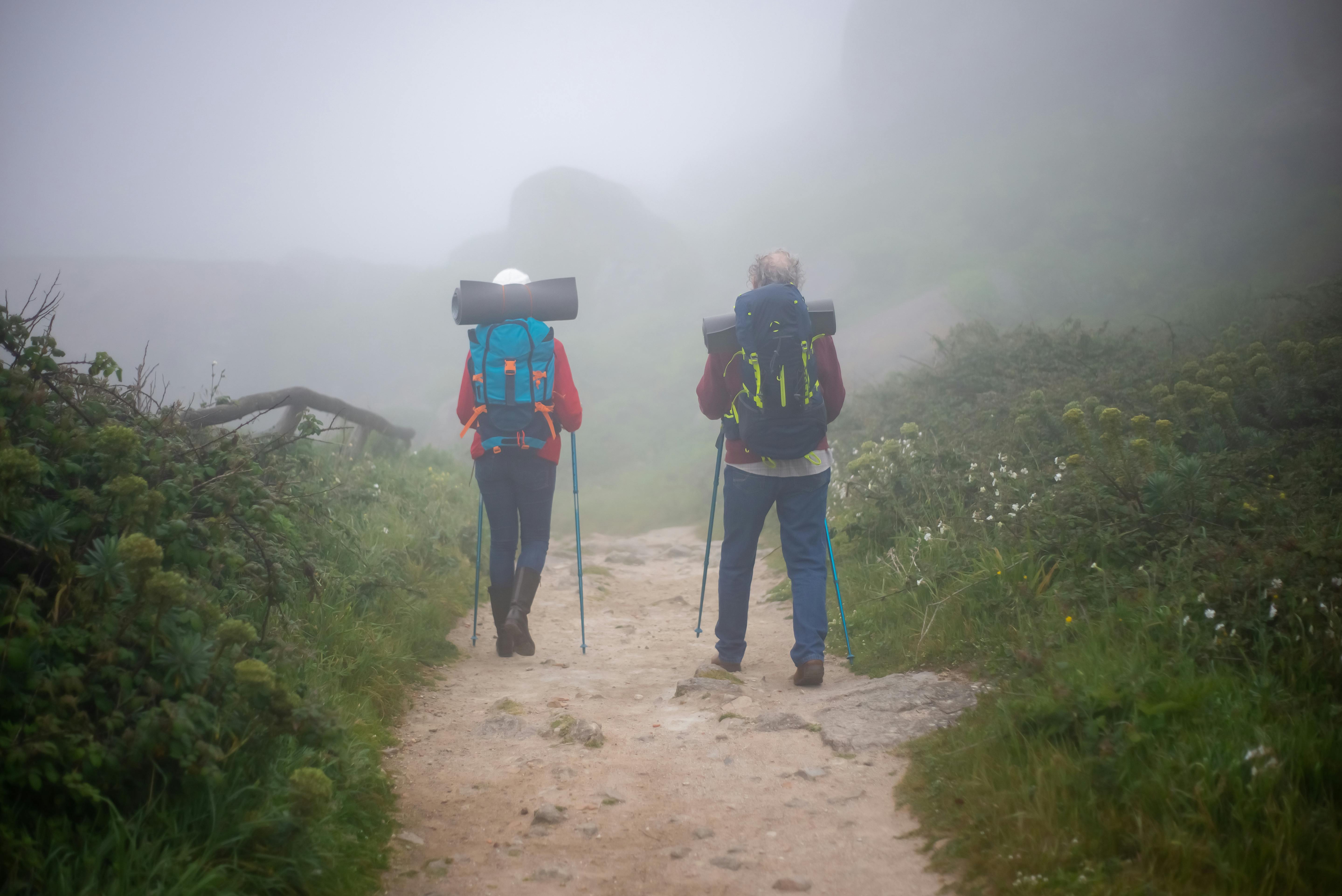 People Wearing Backpacks Walking on Brown Dirt Road · Free Stock Photo