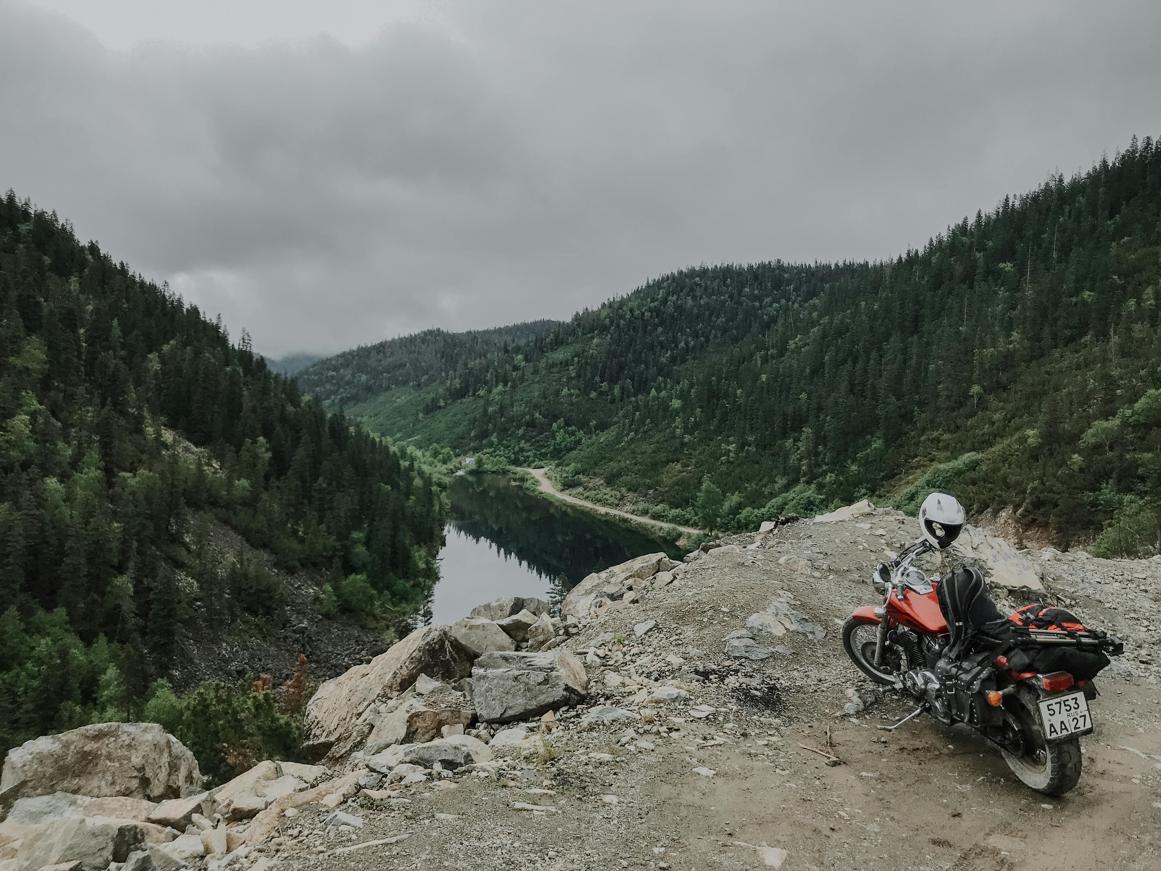 Motorbike on top of rocky cliff under mountain river · Free Stock Photo