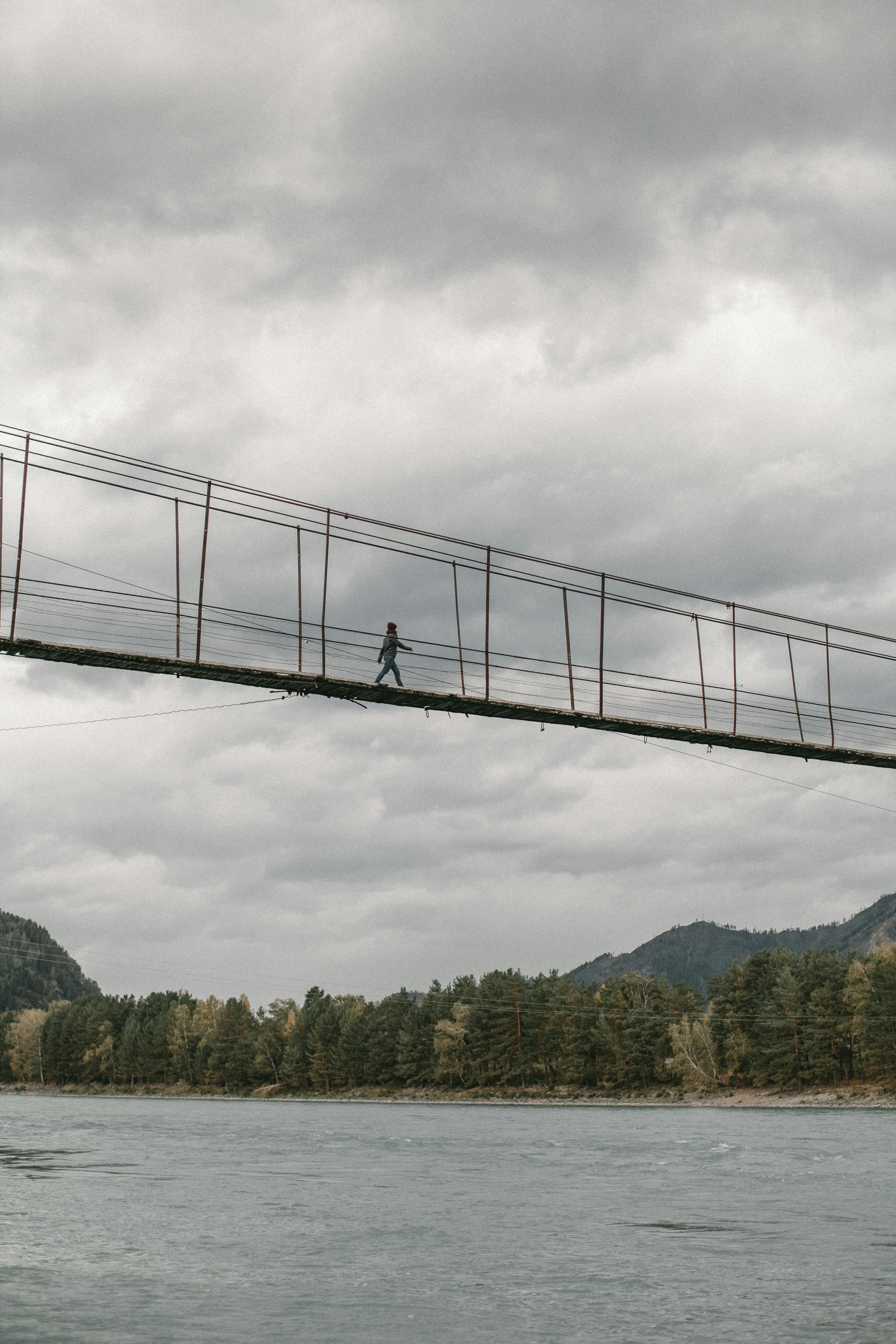 Person Crossing a Footbridge Over a River · Free Stock Photo
