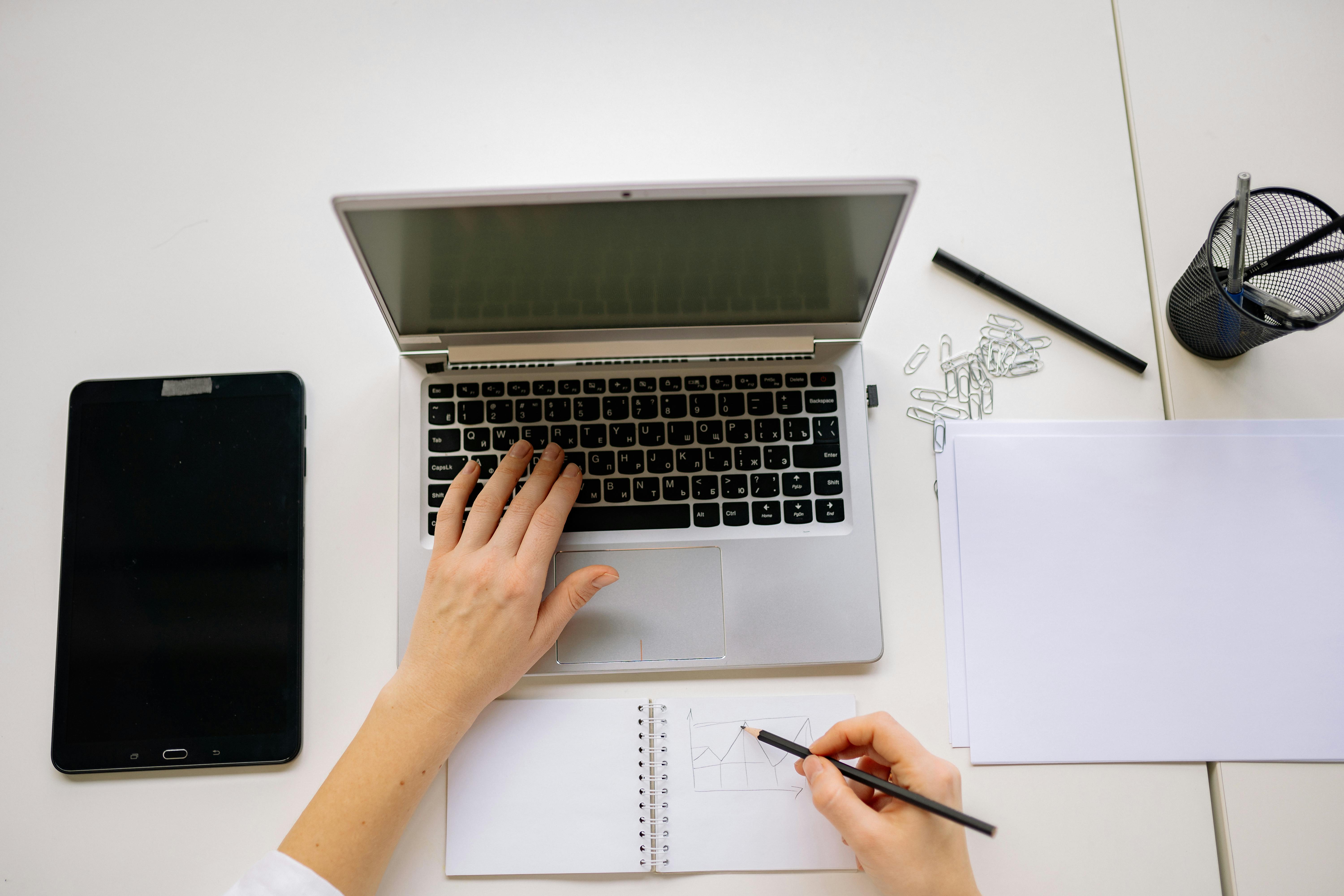 A Person Sketching While Using a Laptop · Free Stock Photo