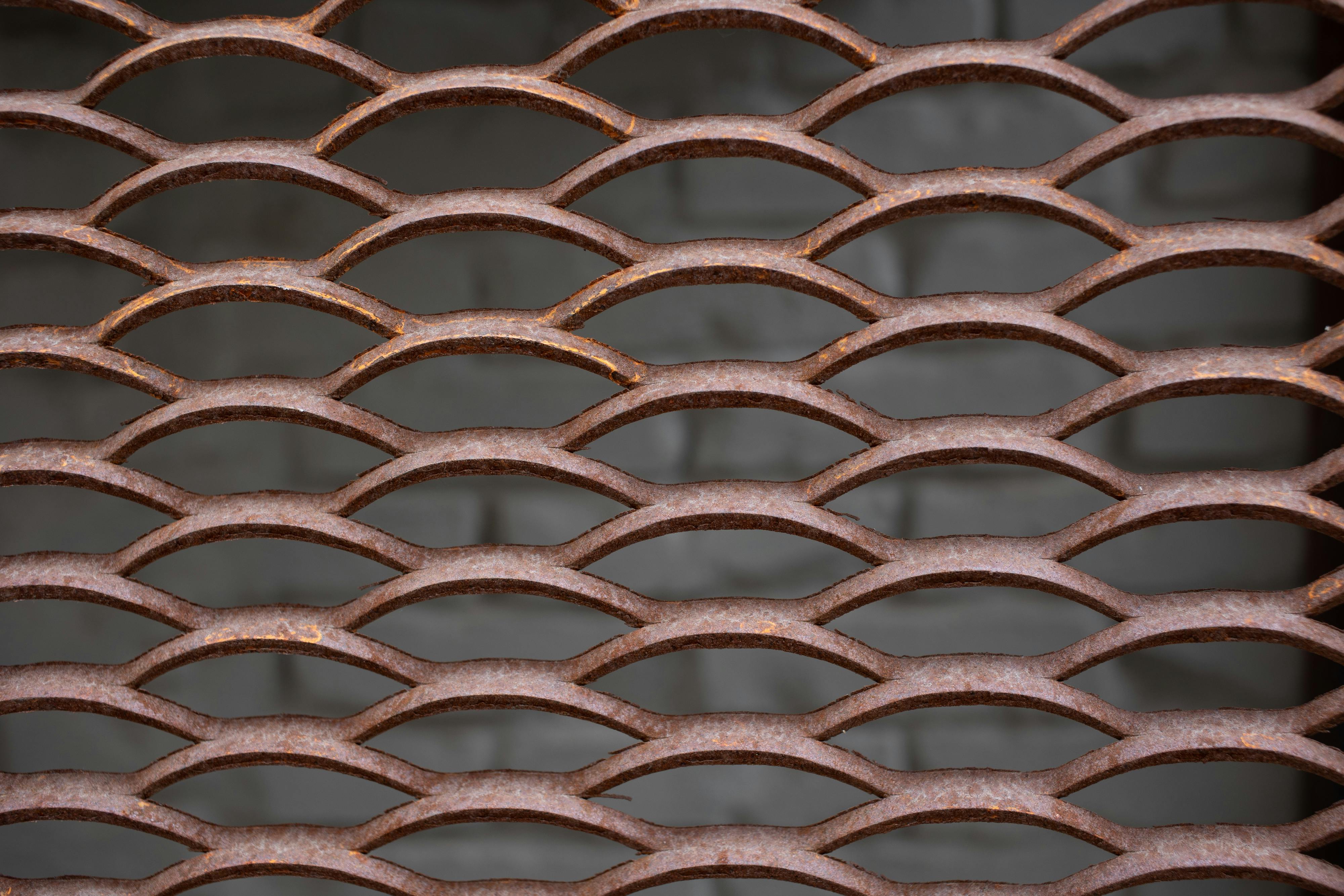Textured background of metal lattice against brick wall · Free Stock Photo