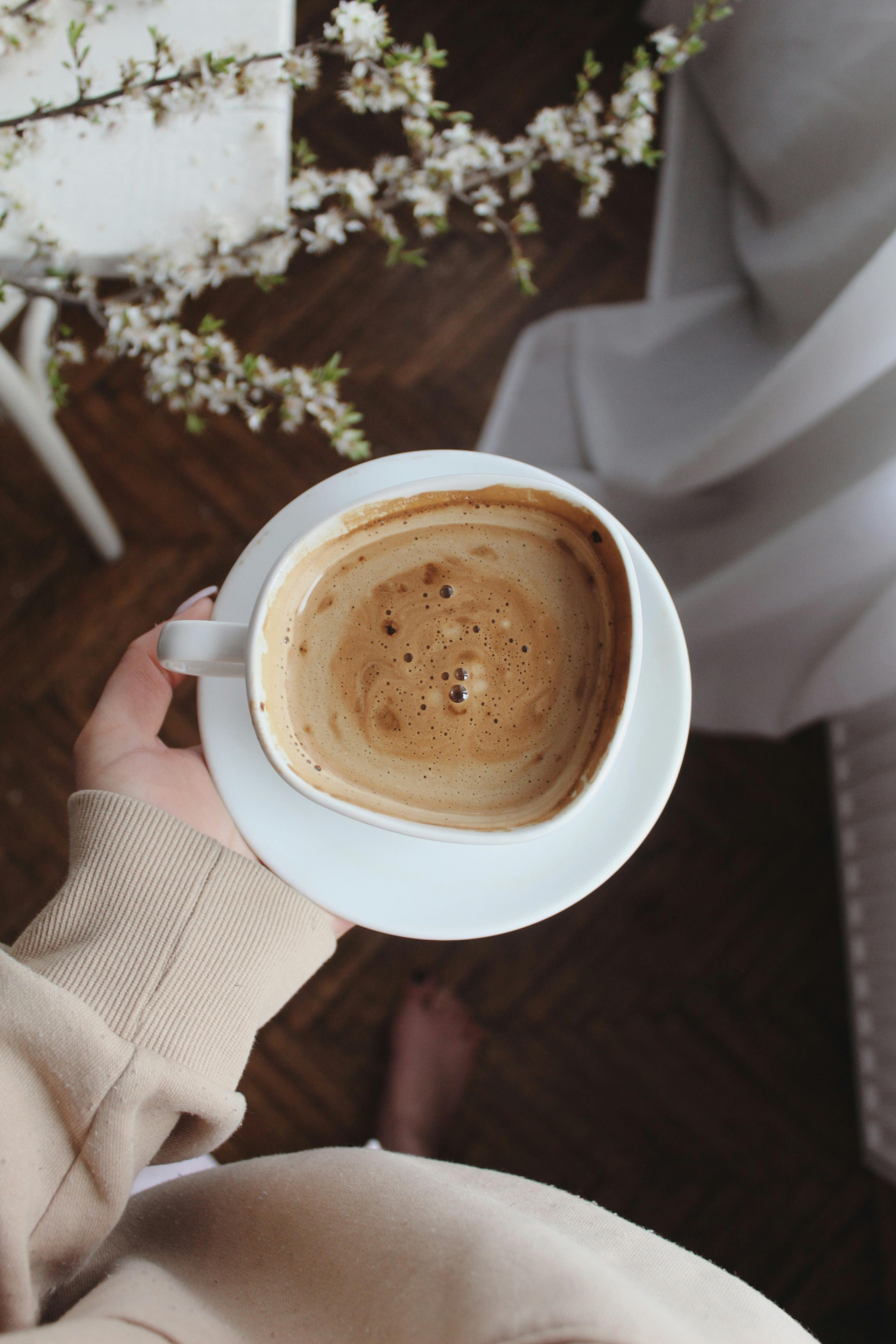 Faceless woman with coffee near blooming branches · Free Stock Photo