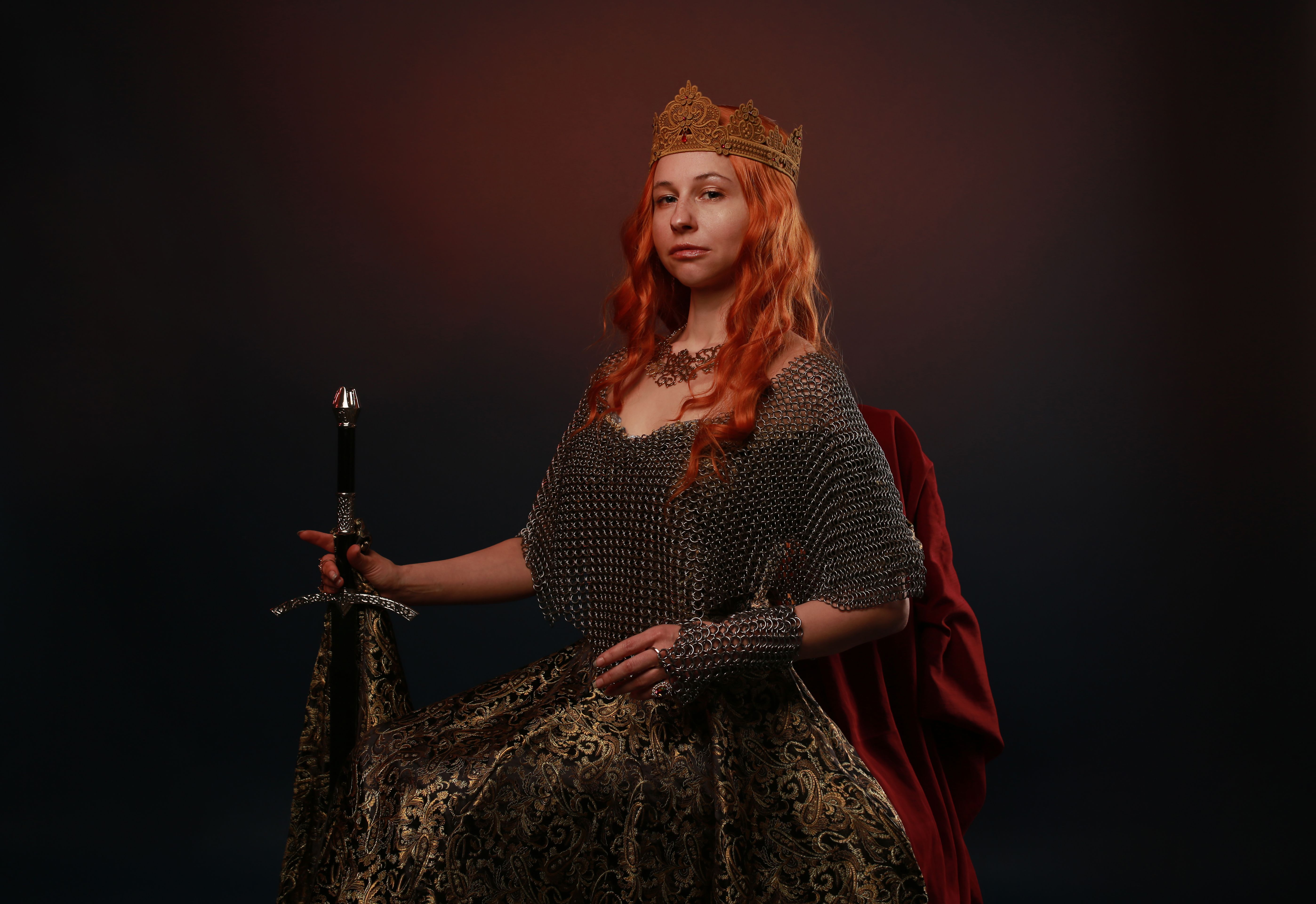 A Woman Wearing a Crown Sitting on a Chair Holding a Sword while ...