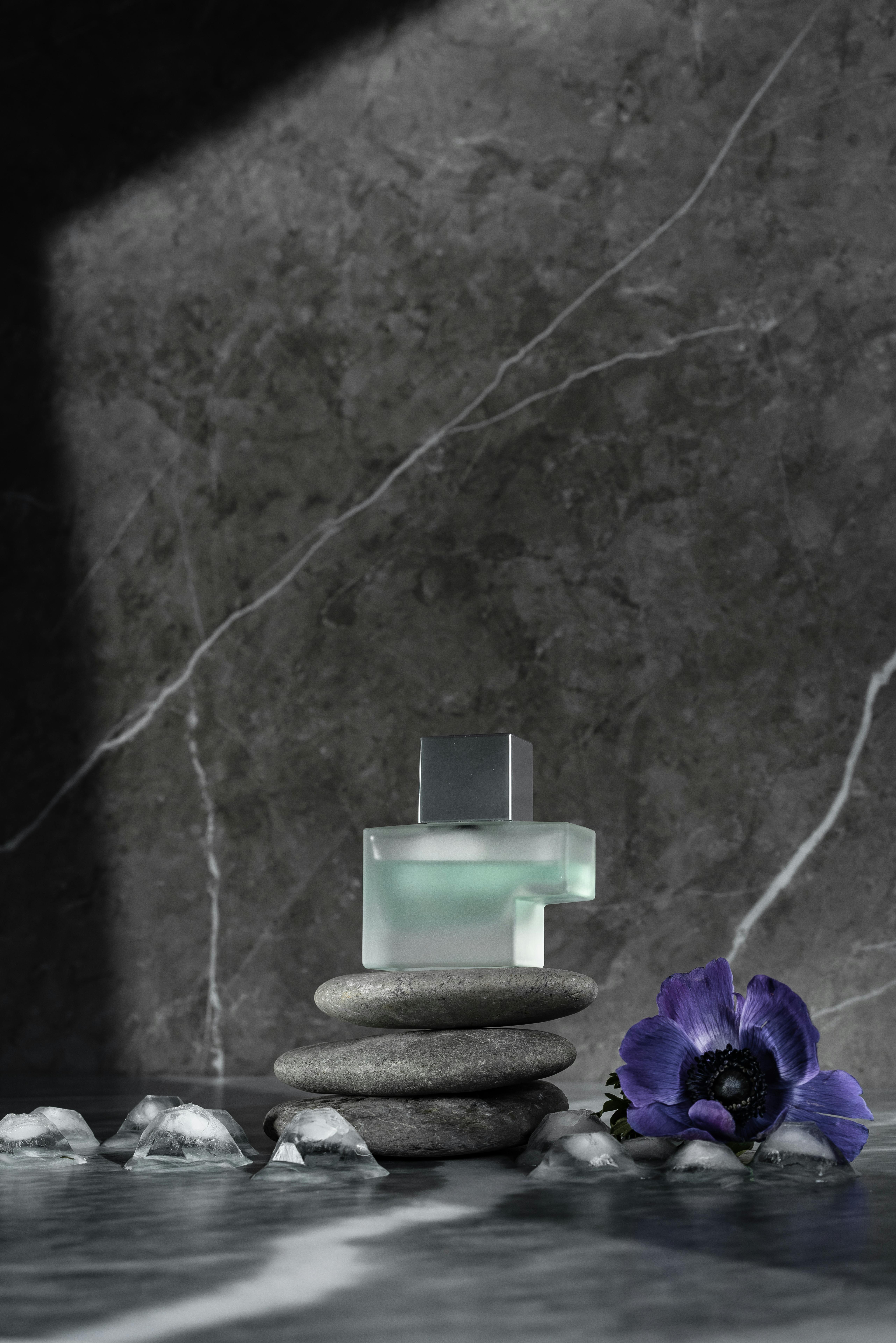 A Bottle of Perfume Standing on a Stack of Stones on Gray Background ...