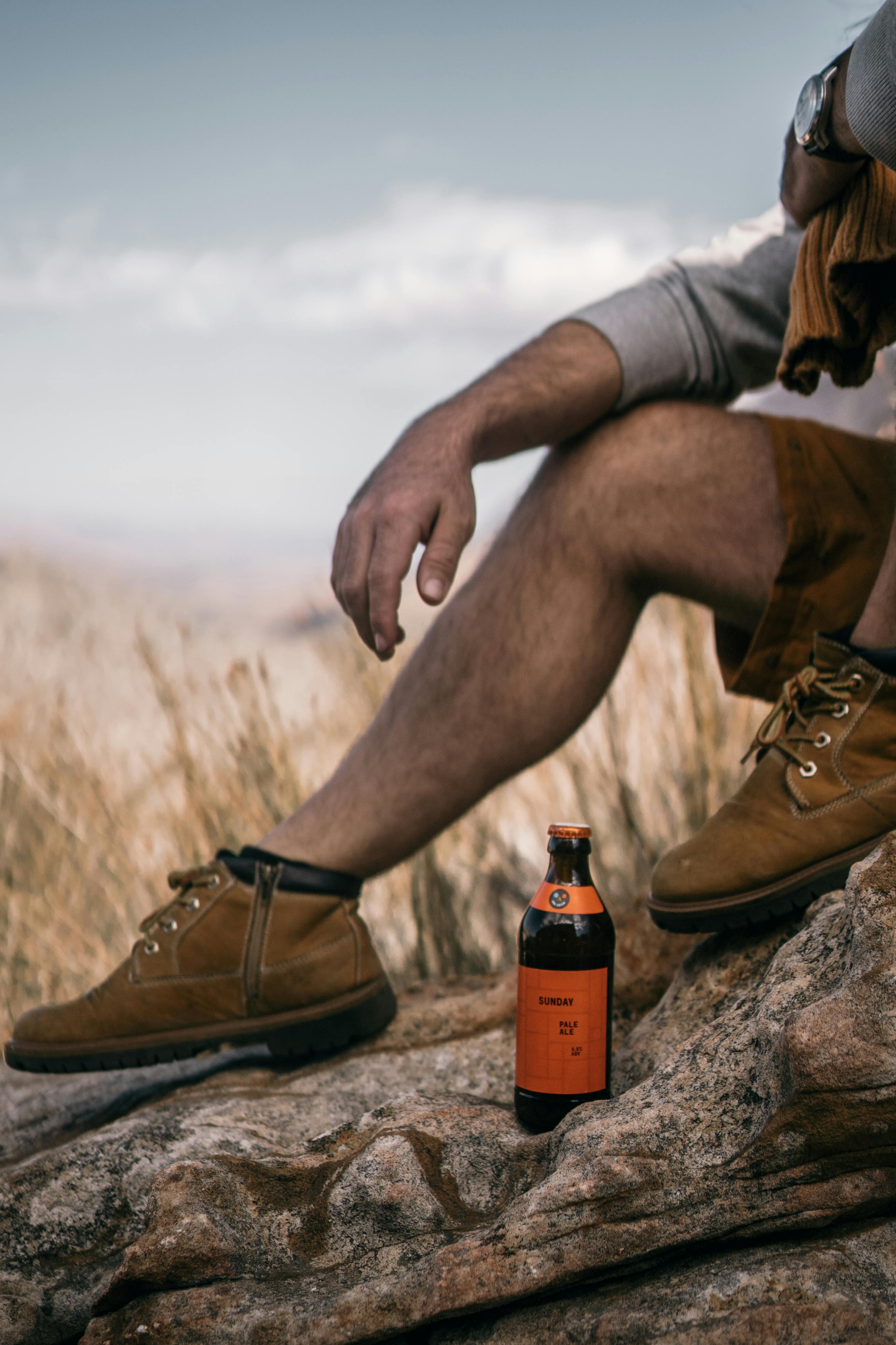 Photo of a Beer Bottle Near a Person's Feet · Free Stock Photo