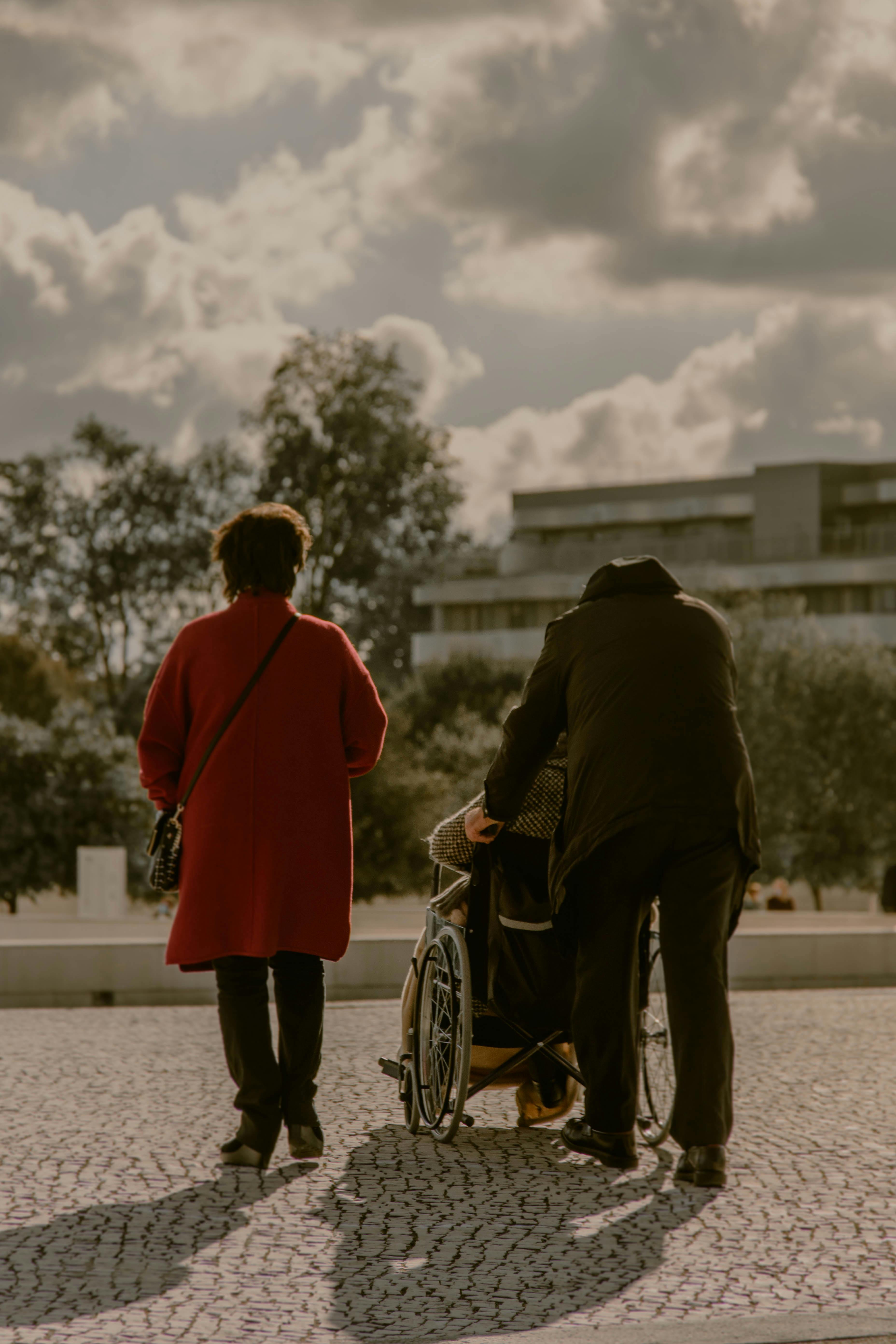 Back View of Two People Walking with a Person in a Wheelchair · Free ...