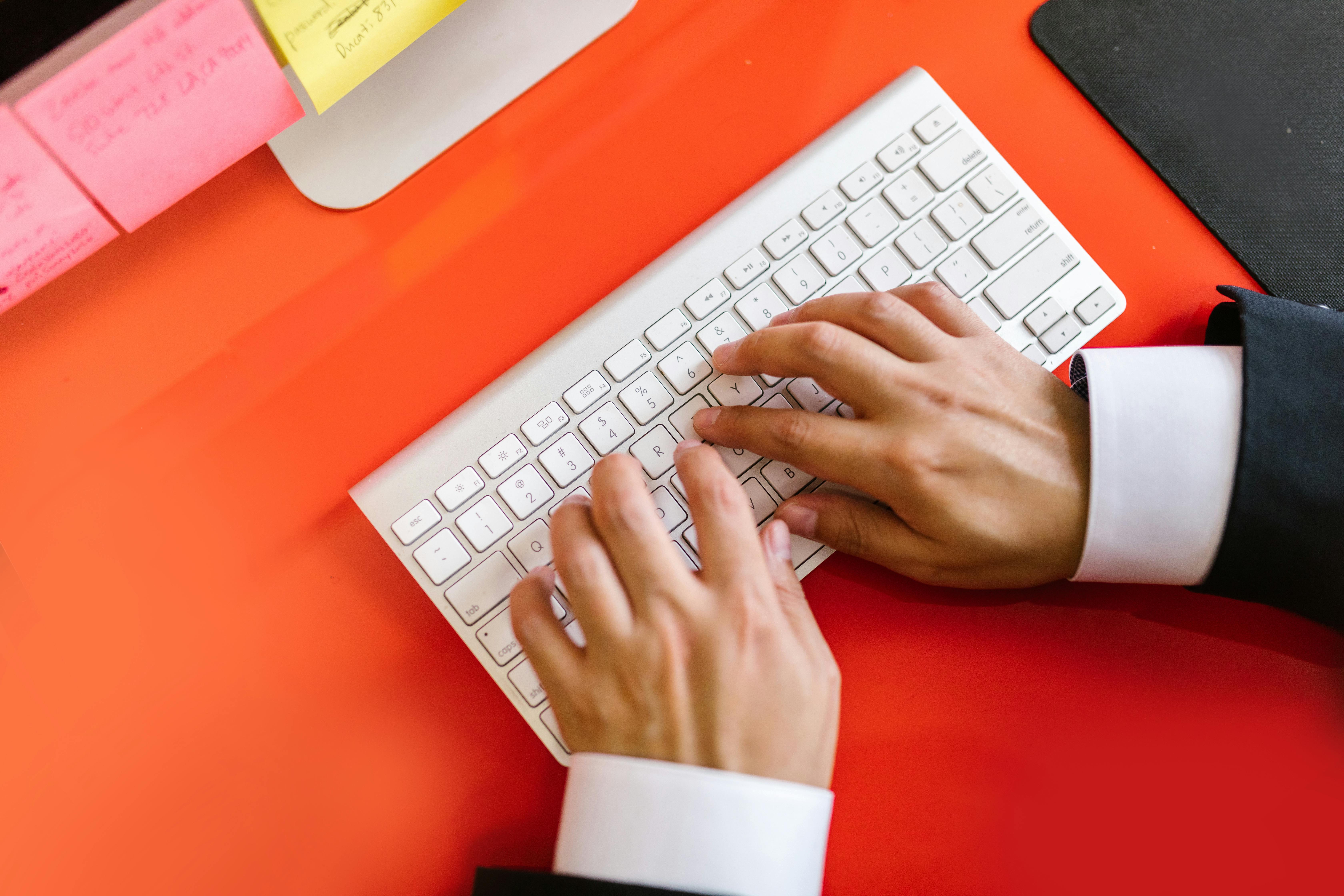 Man in Striped Polo Shirt Typing on White Keyboard · Free Stock Photo
