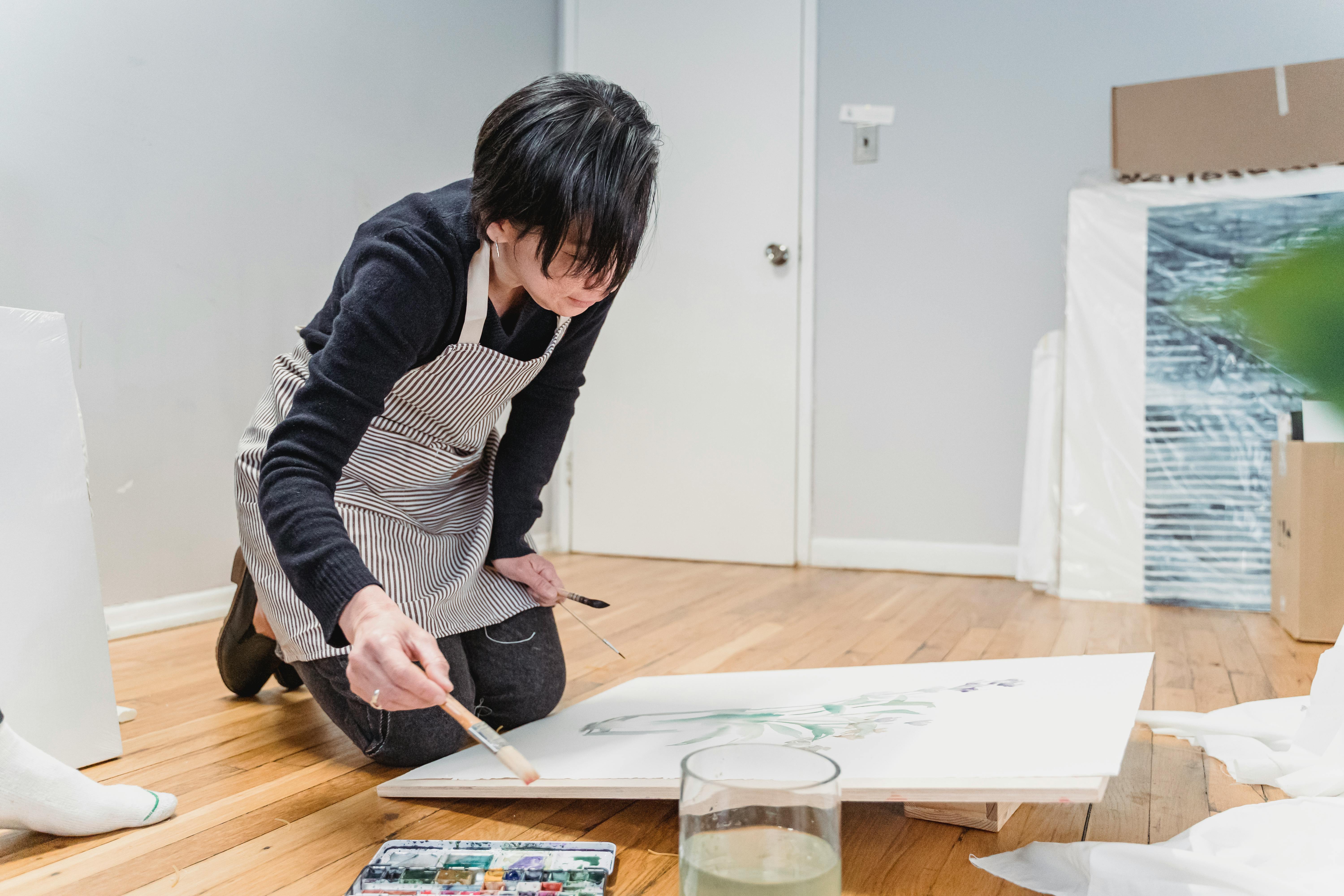 Young artist sitting on floor with artworks · Free Stock Photo