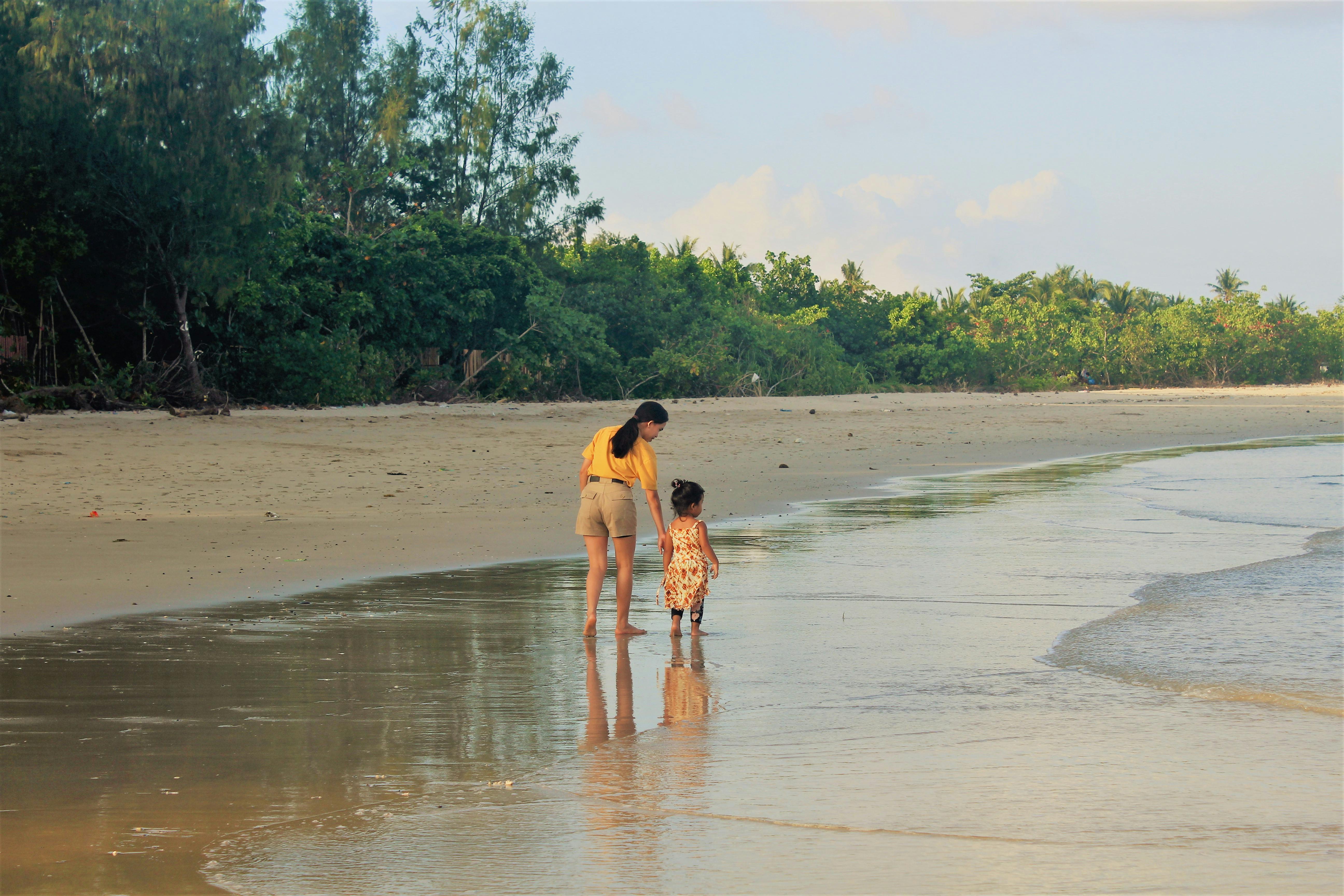 A Woman and a Young Girl Walking on the Beach · Free Stock Photo