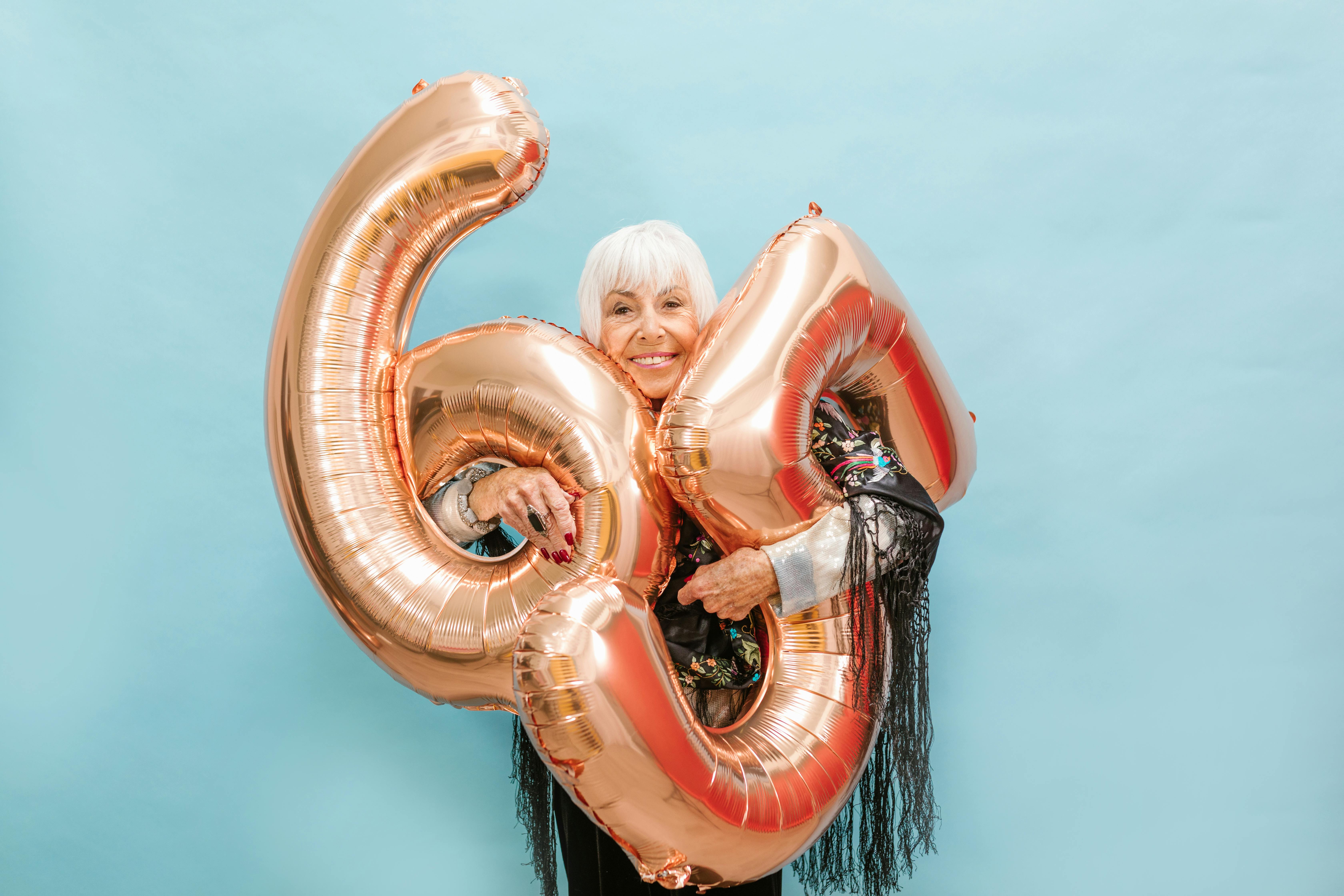 A Happy Old Woman Holding Inflatable Numbers · Free Stock Photo