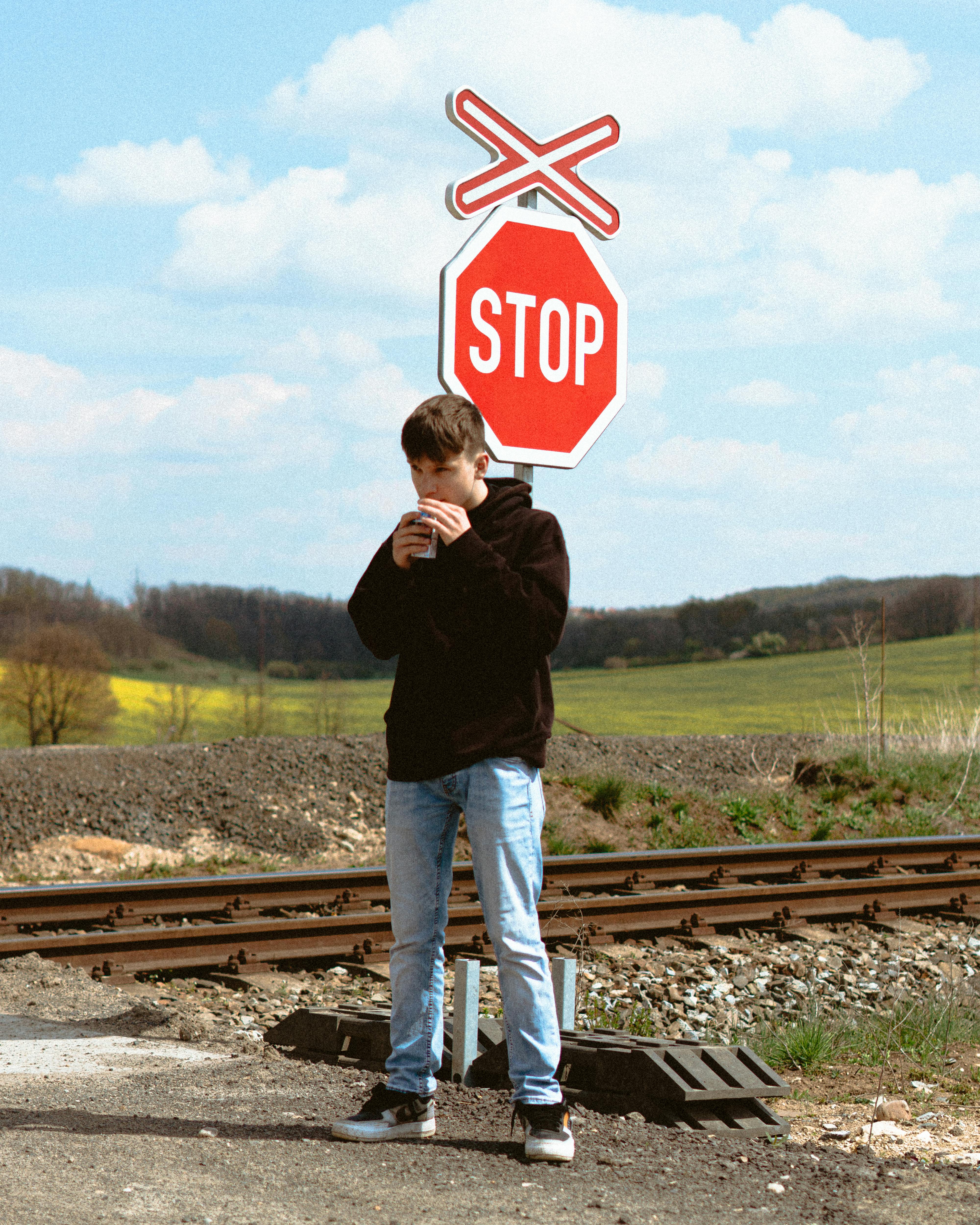A Man Standing Beside Stop Sign · Free Stock Photo