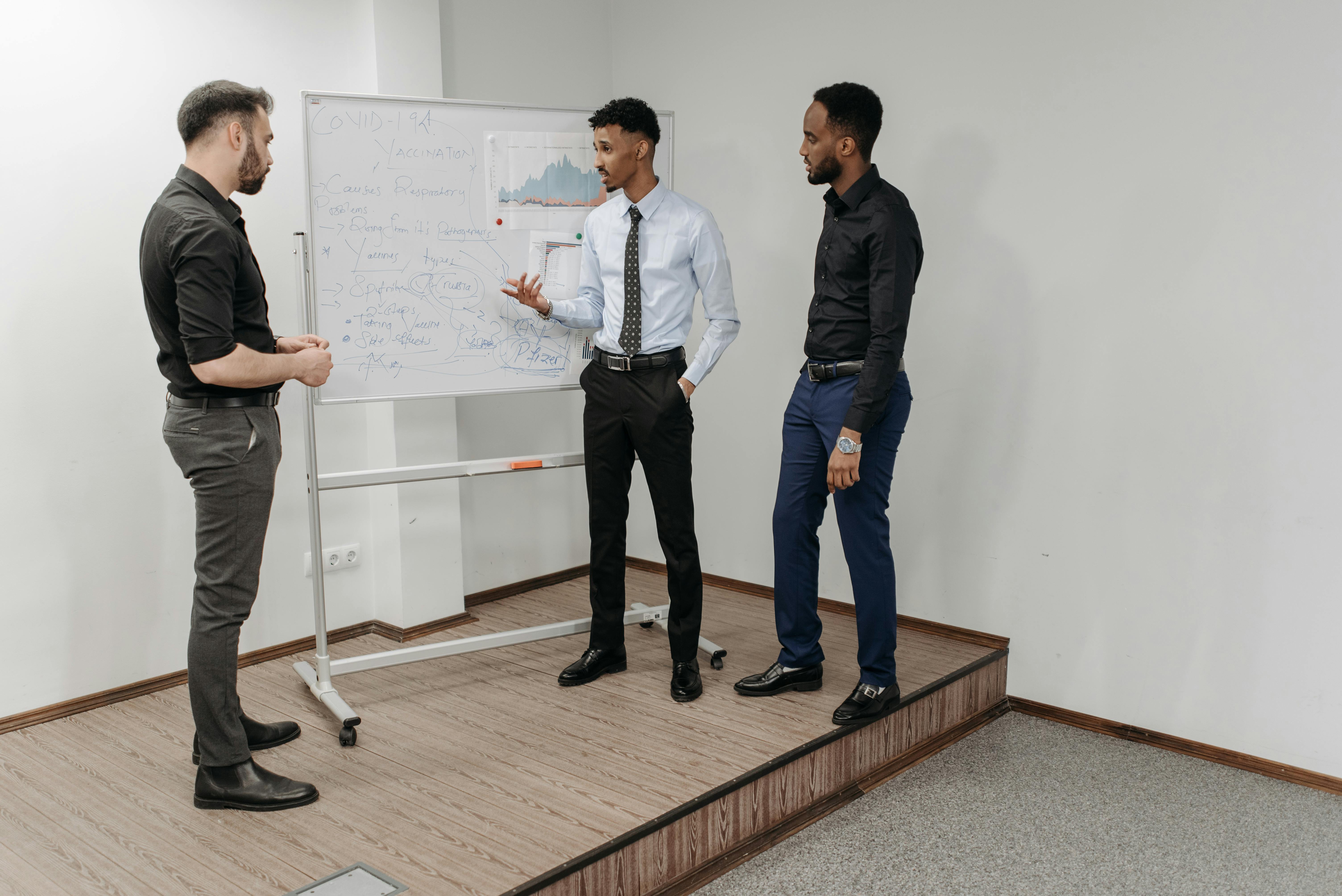 Men Discussing Near a White Board in a Meeting Room · Free Stock Photo