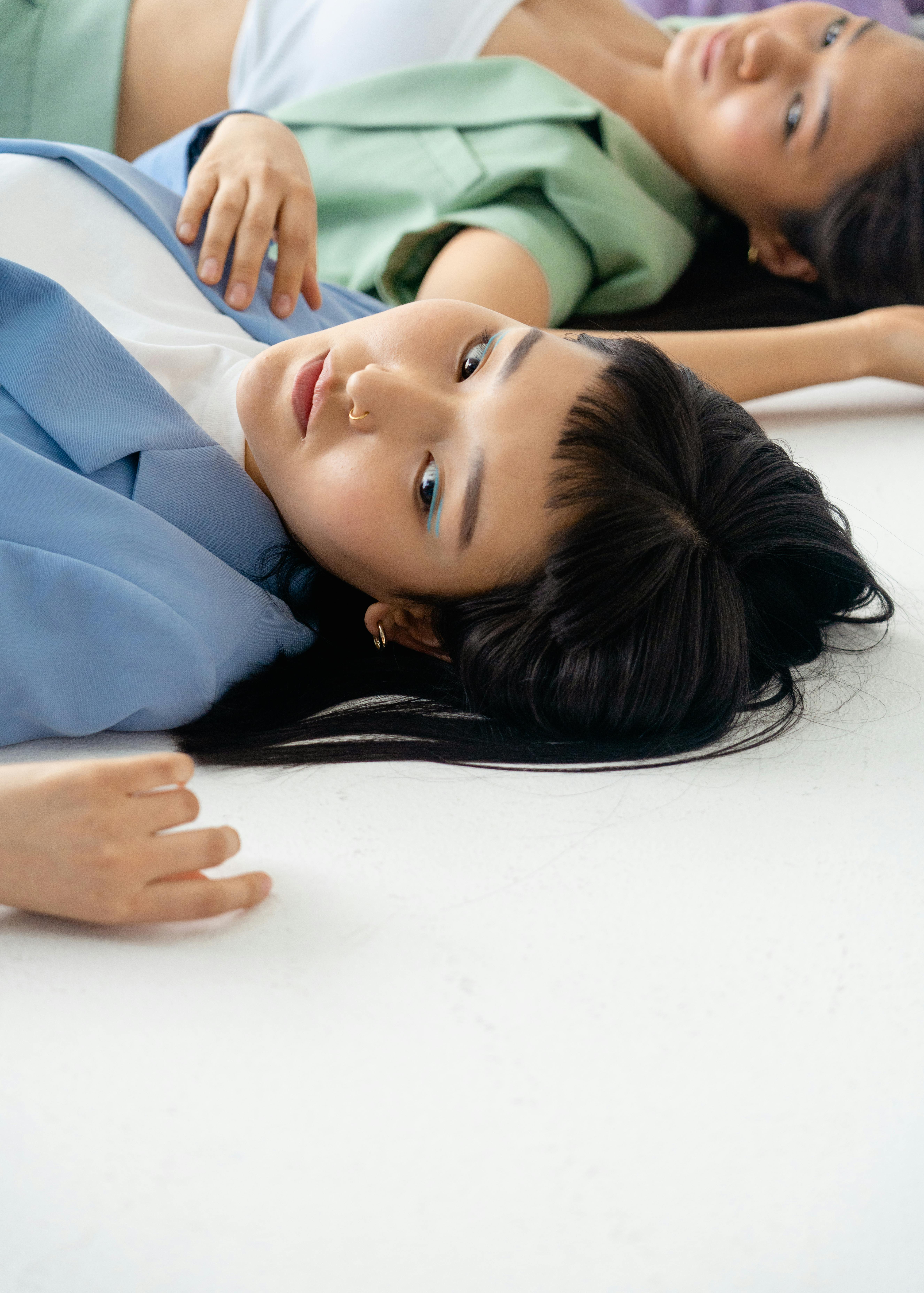 Women in Pastel Colored Jackets Lying Down on the Floor · Free Stock Photo