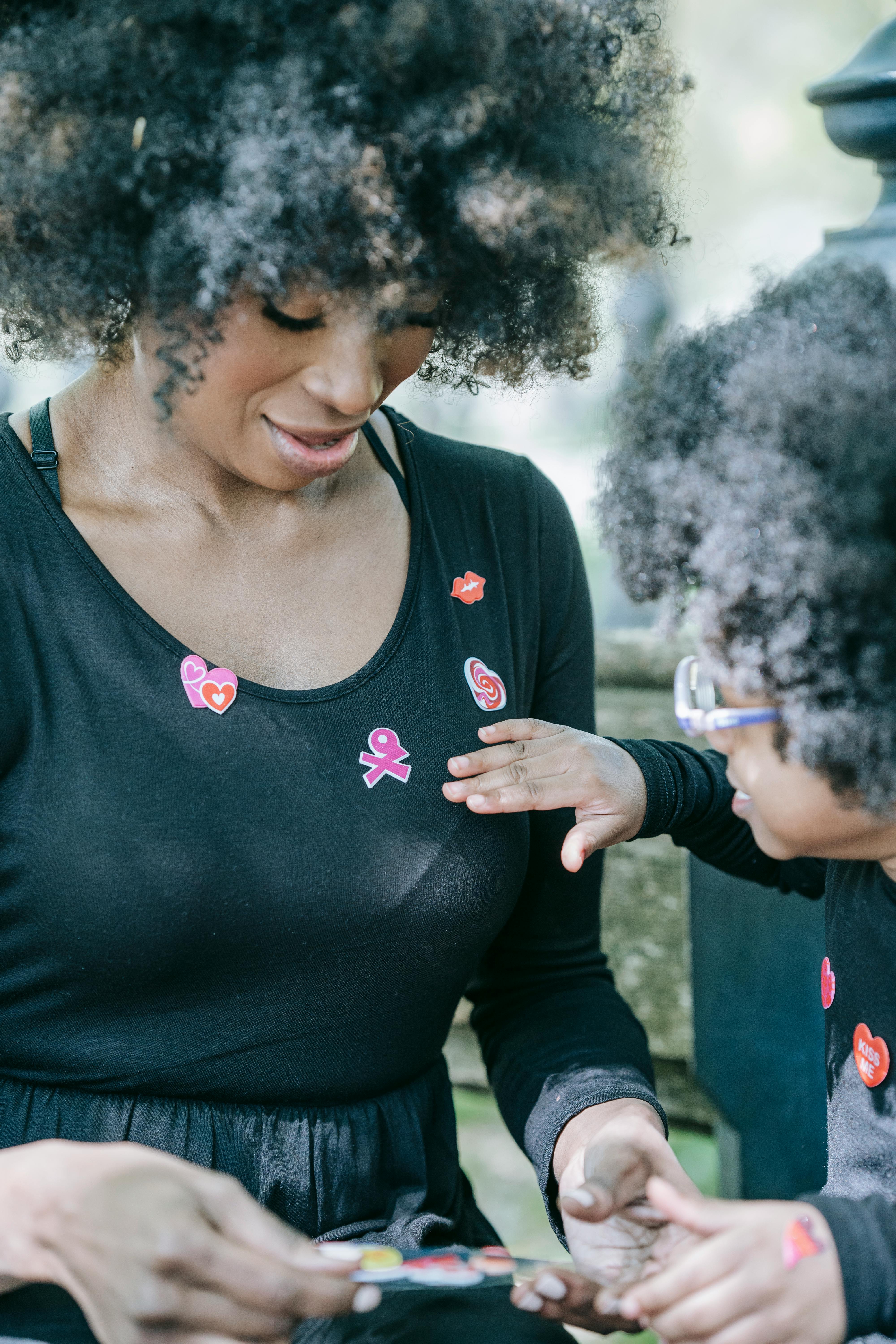 A Child Putting Stickers on Woman's Black Long Sleeves · Free Stock Photo