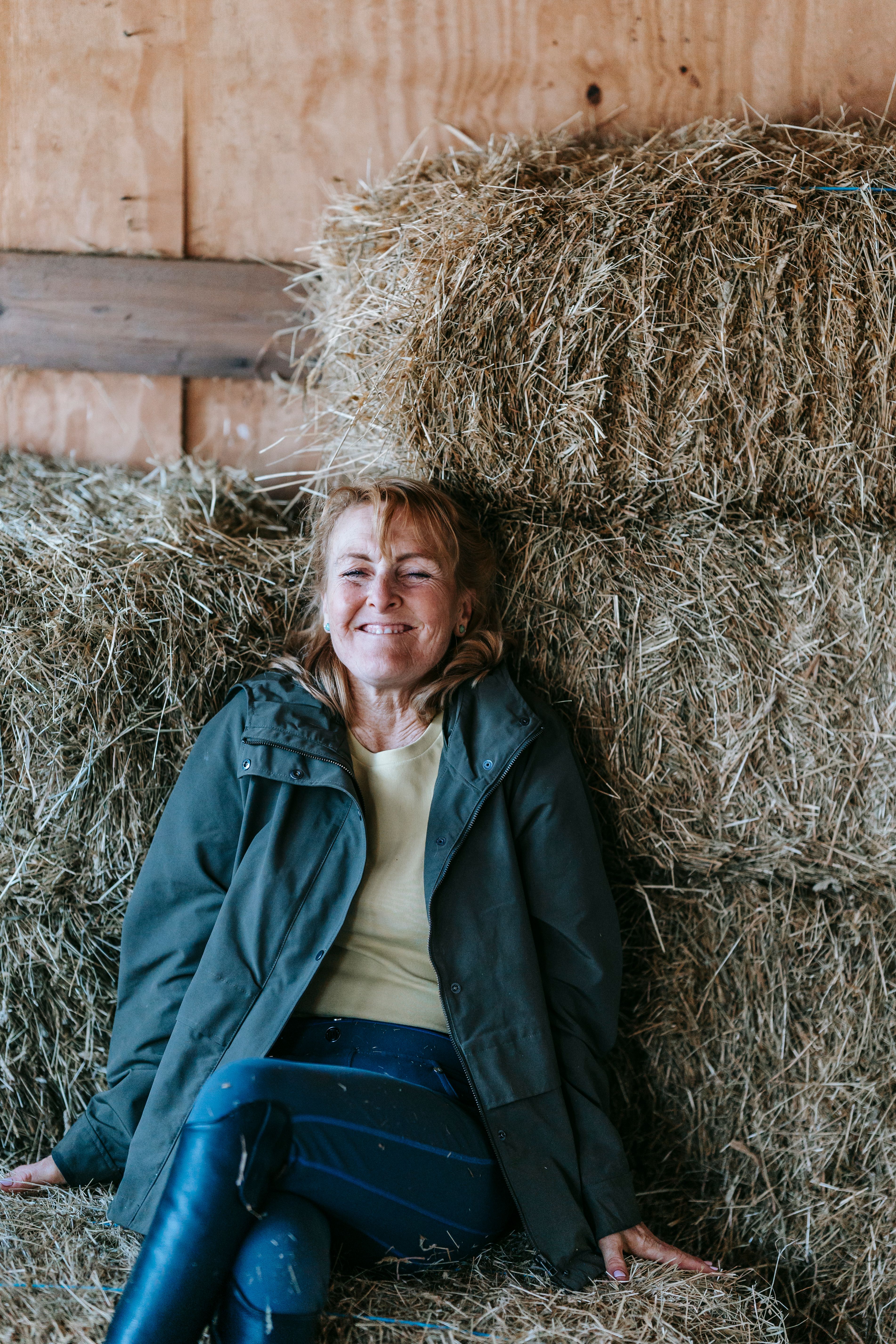 A Woman Smiling Sitting on a Haystack · Free Stock Photo