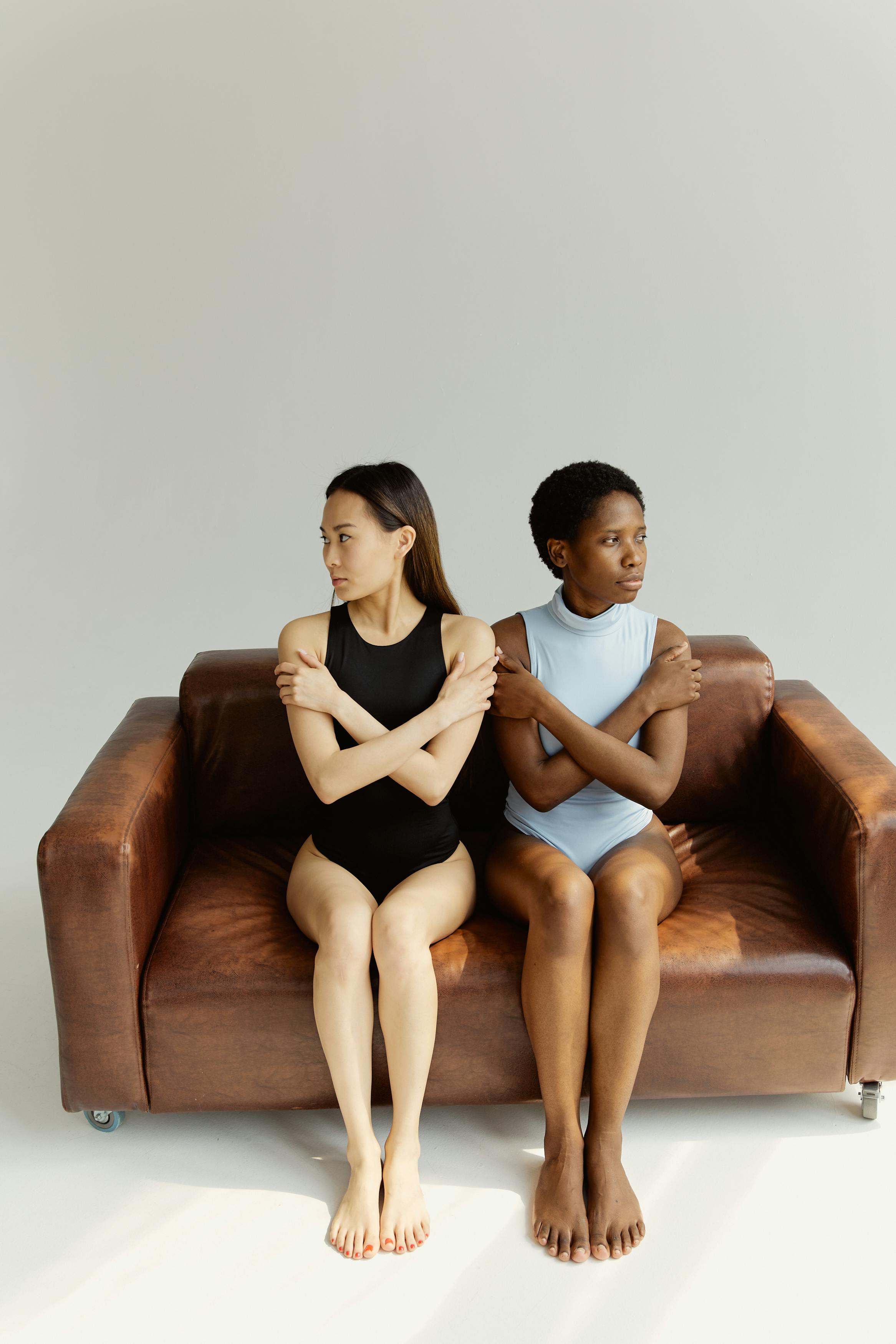Two Women Sitting on Brown Couch Posing · Free Stock Photo
