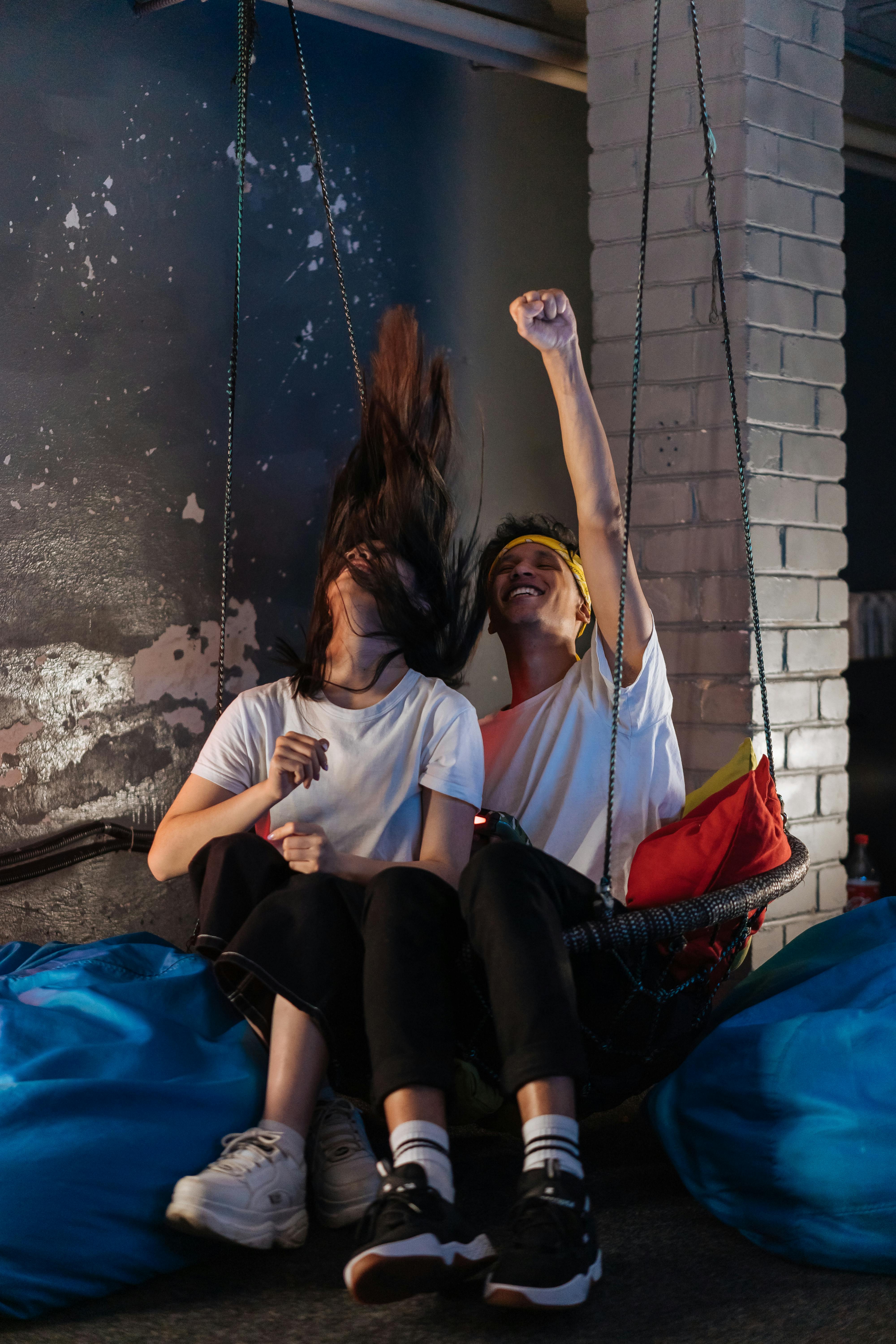 Victorious Friends sitting in a Hanging Chair · Free Stock Photo