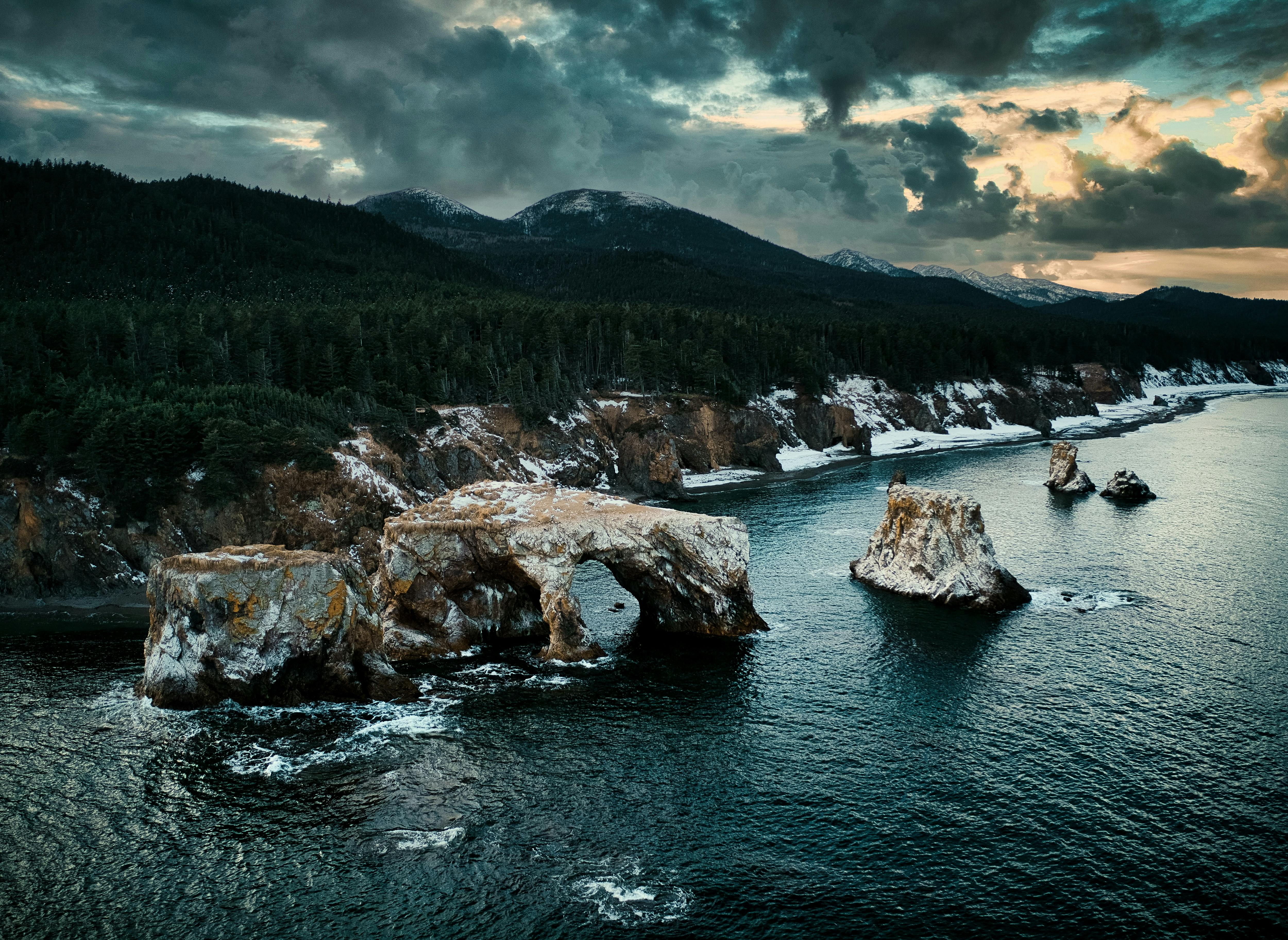 Rock Formations Along a Coastline Under Gloomy Sky · Free Stock Photo