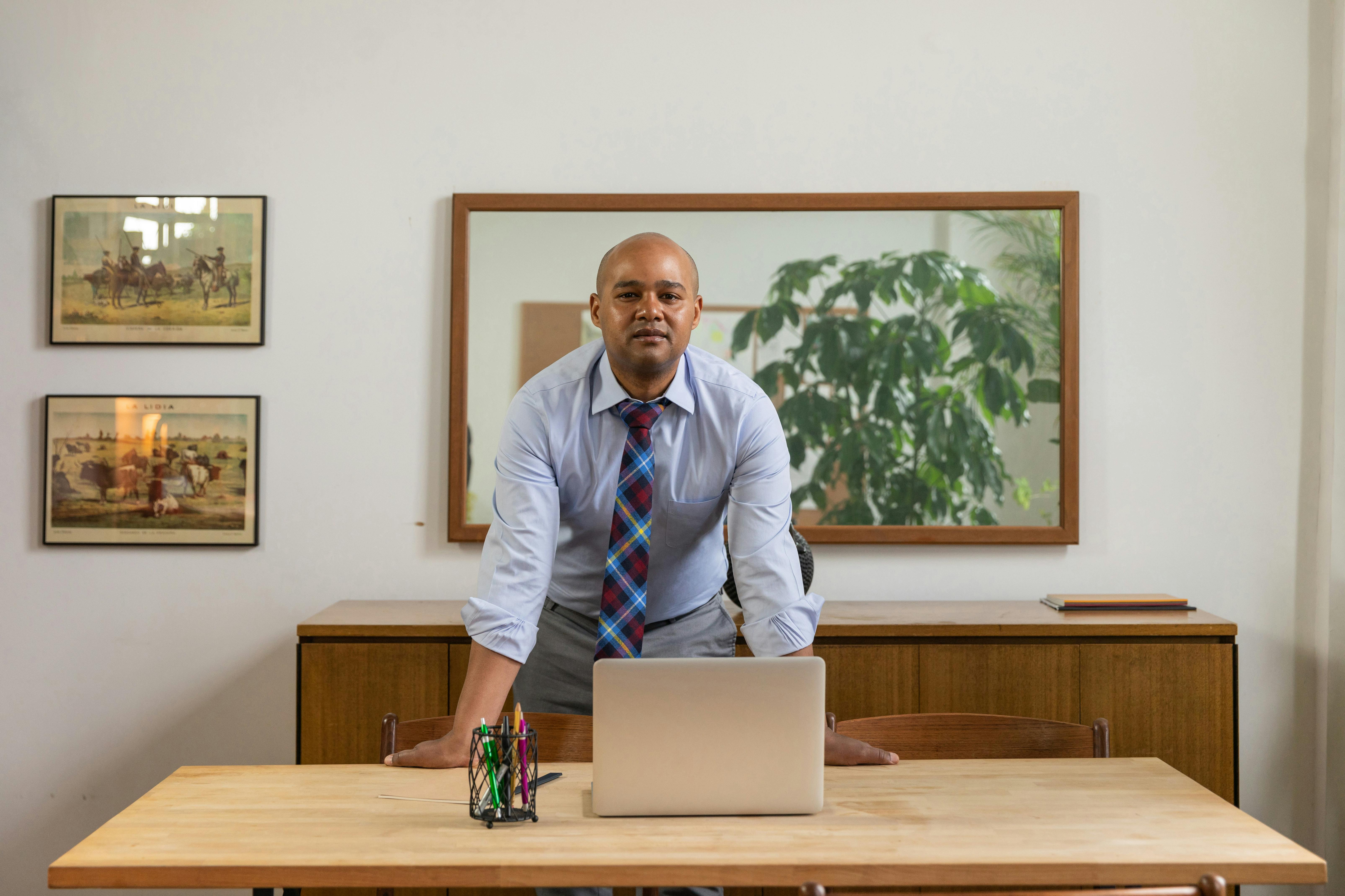 A Man in Blue Long Sleeves Standing Behind His Desk · Free Stock Photo